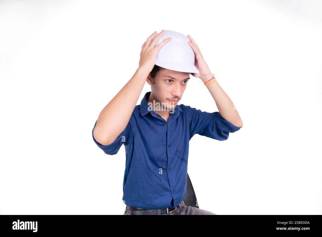 Studio portrait of young architect adjusting white helmet on head ...
