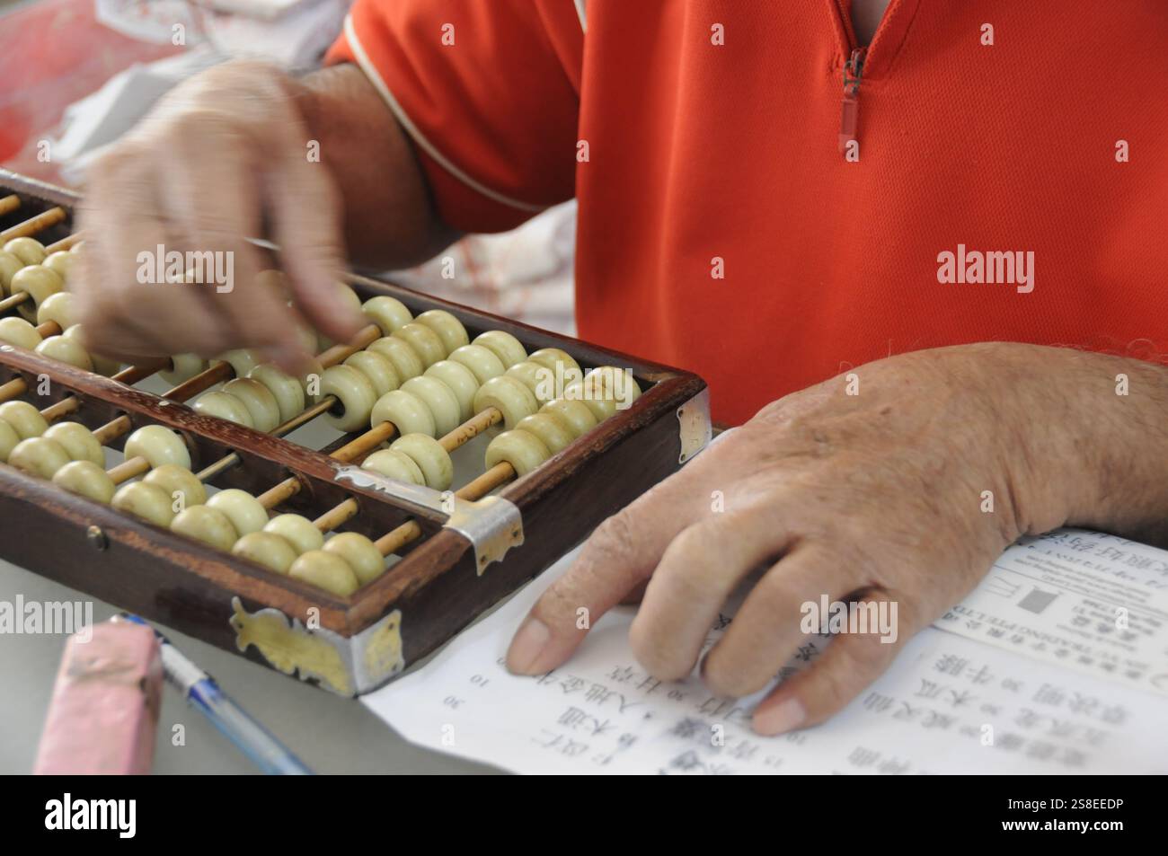 A Chinese trader using a Chinese abacus, also known as the suanpan at a ...