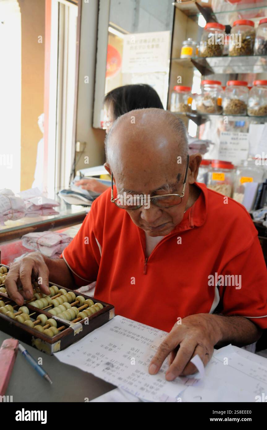 A Chinese trader using a Chinese abacus, also known as the suanpan at a ...