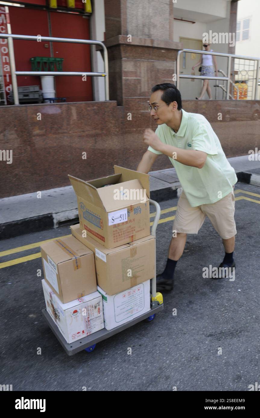 A market trader pushing is trolley load of mixed goods in the ...