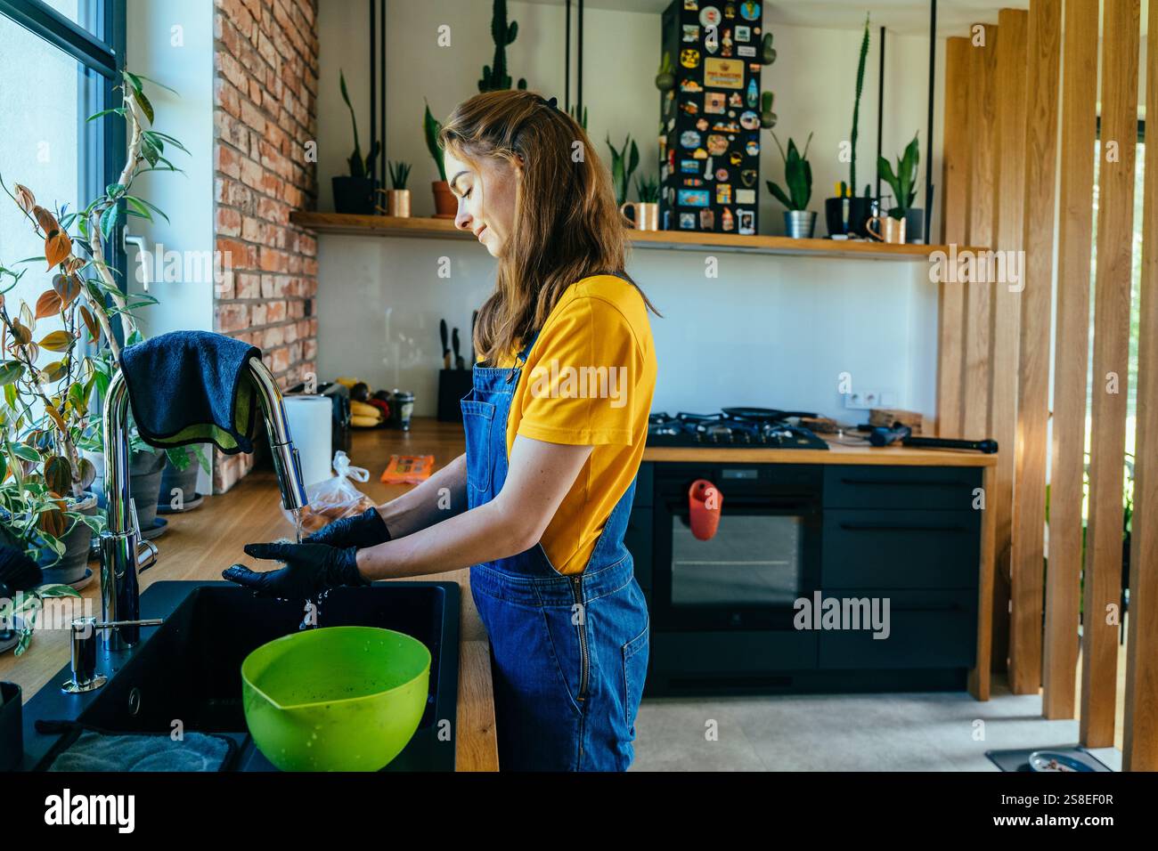 Side view of nice looking woman gardener wearing black gloves washing ...