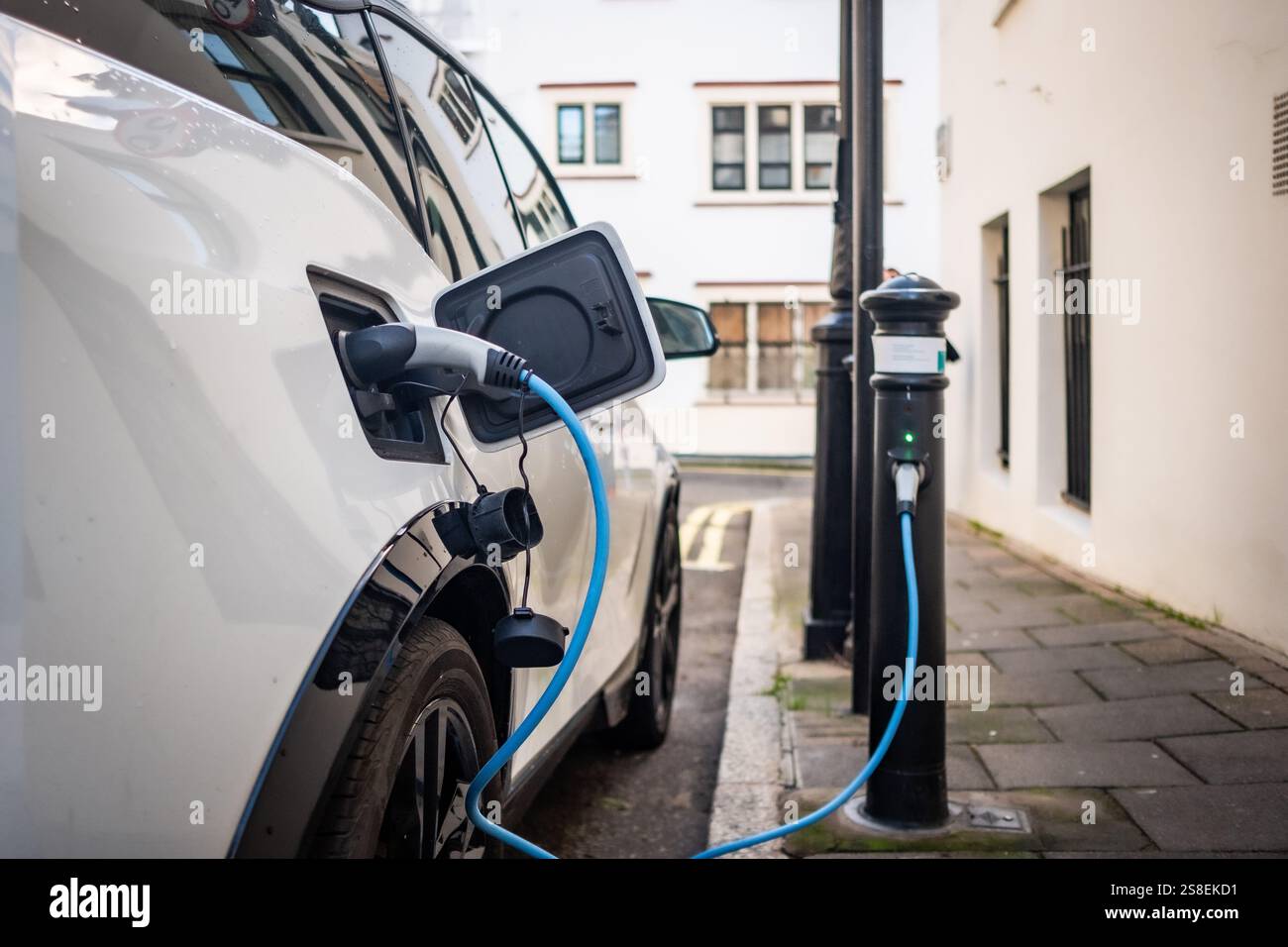 Electric car plugged in and changing on urban city street Stock Photo ...
