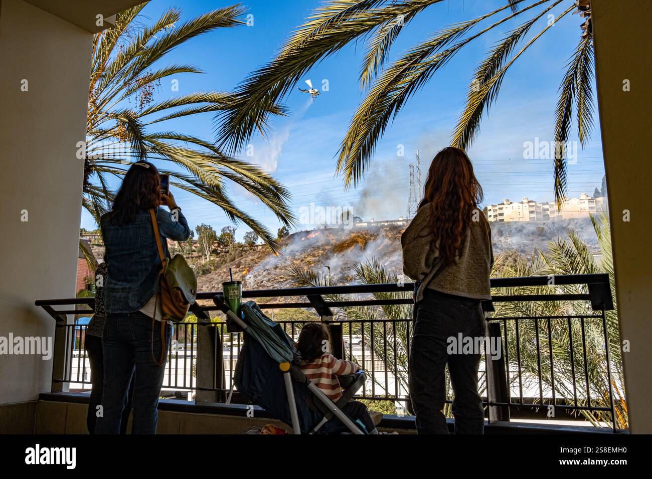 People watch a helicopter drop water on the Friars Fire from Fashion ...
