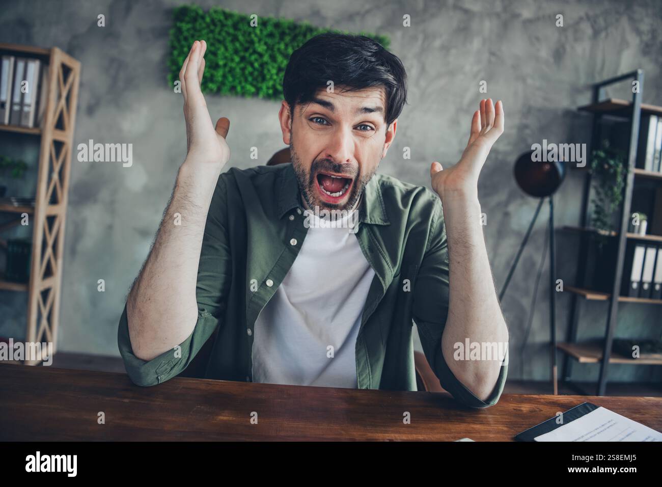 Frustrated young man expressing anger at workplace in casual office ...