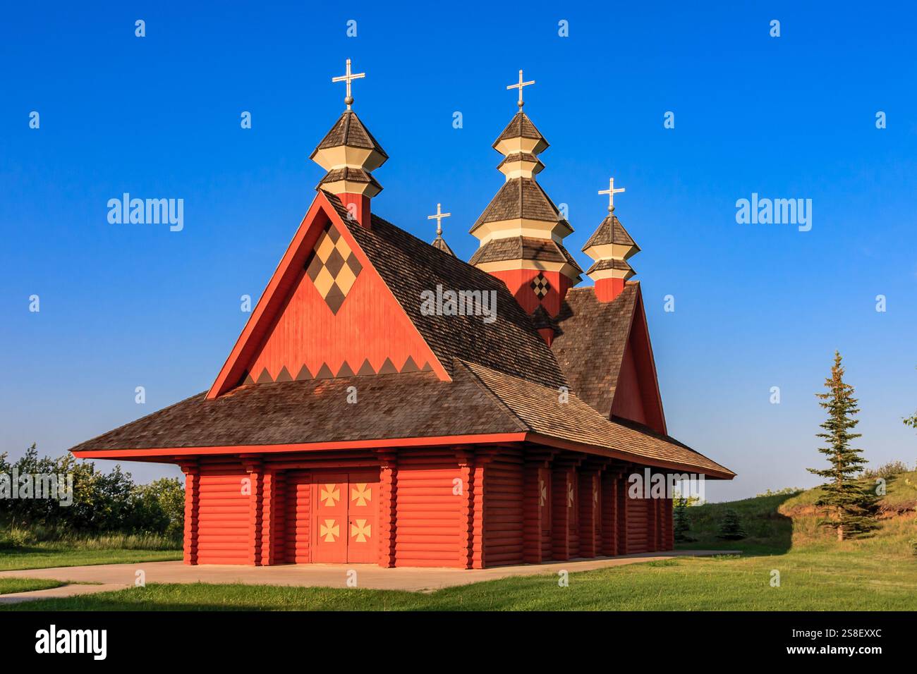 A red church with three crosses on top of it. The sky is blue and the ...