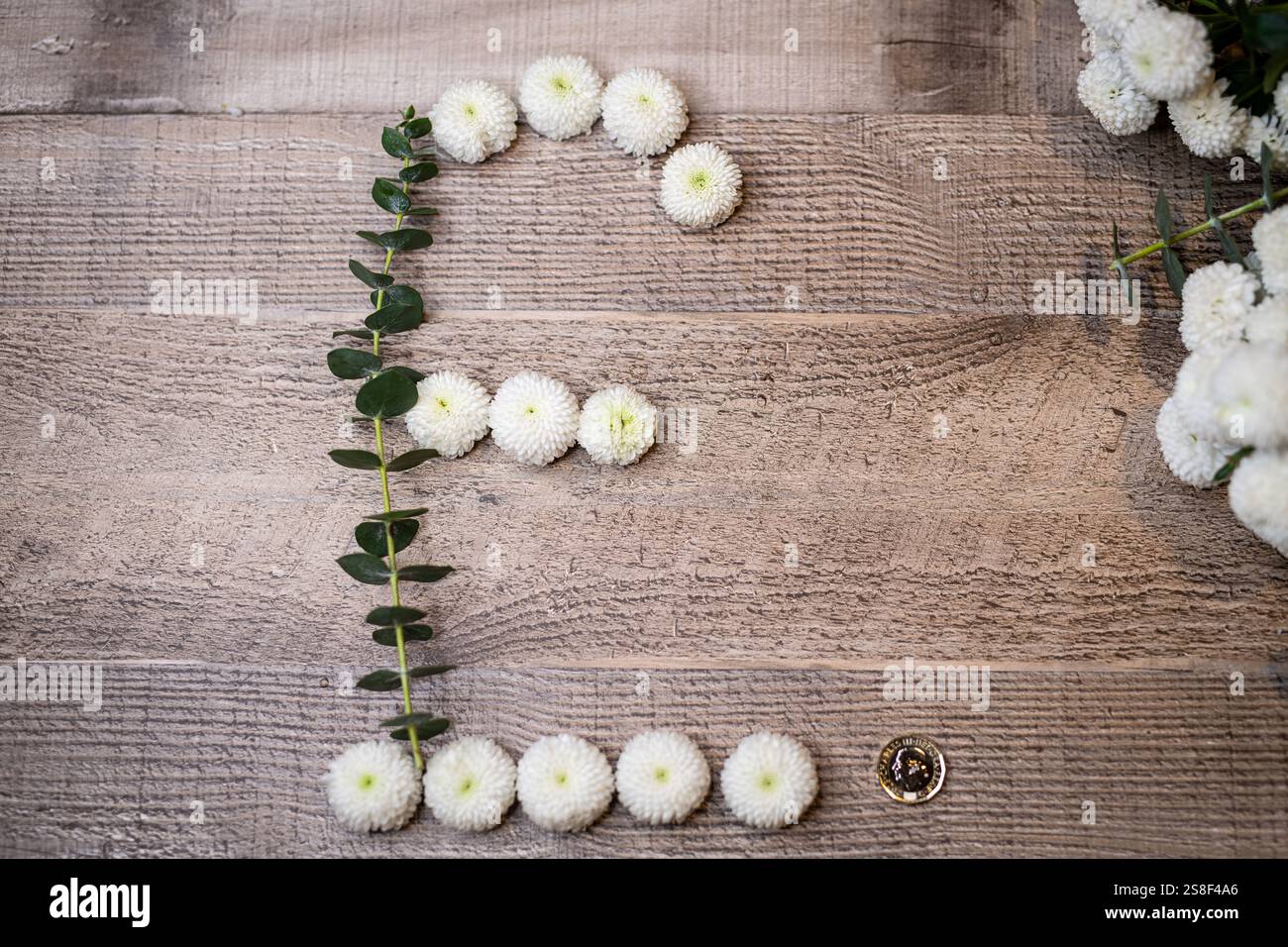 A £ sign made of white vibrant flower heads and eucalyptus sits beside ...