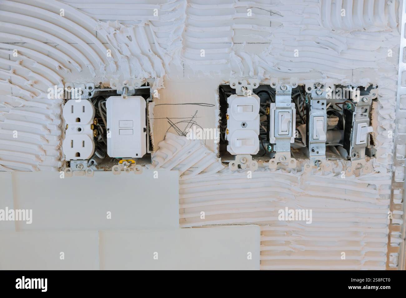 Multiple electrical outlets, switches are being installed on textured ...