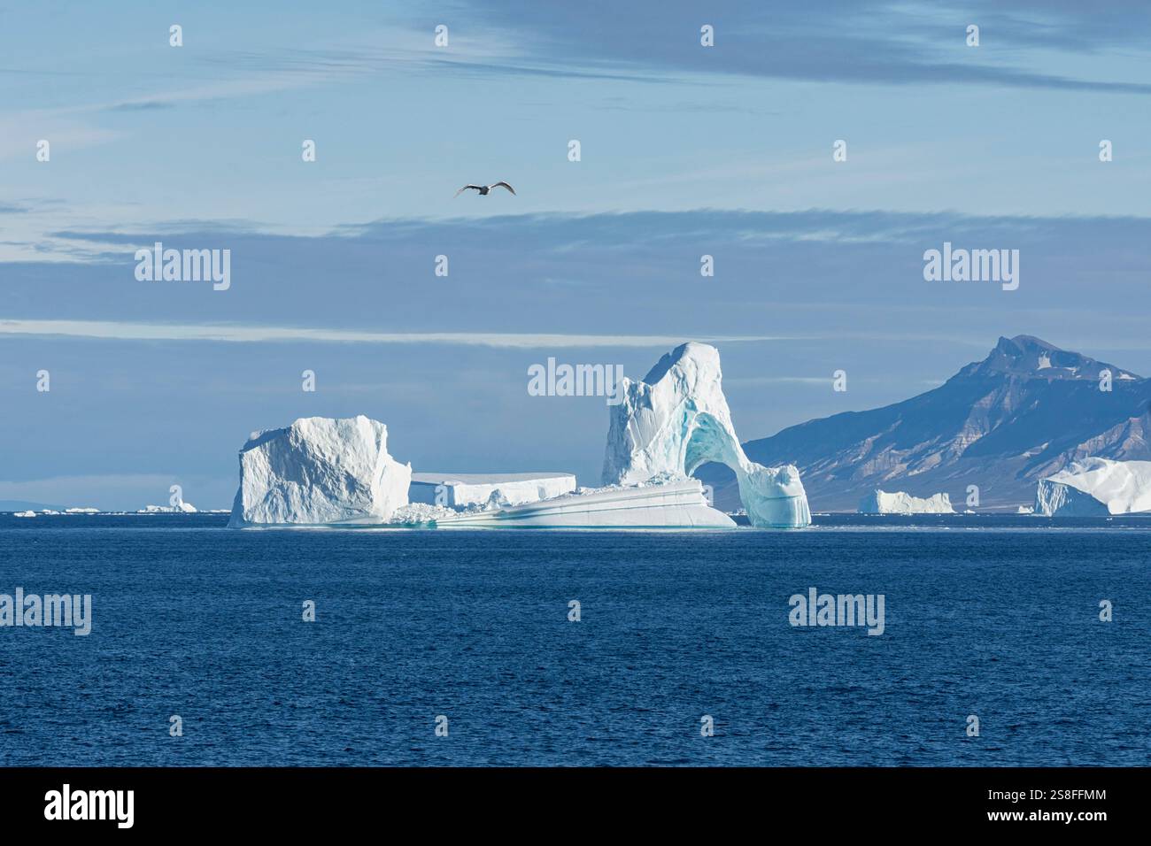 An iceberg with an arch floats in the sea. The arch is about to ...