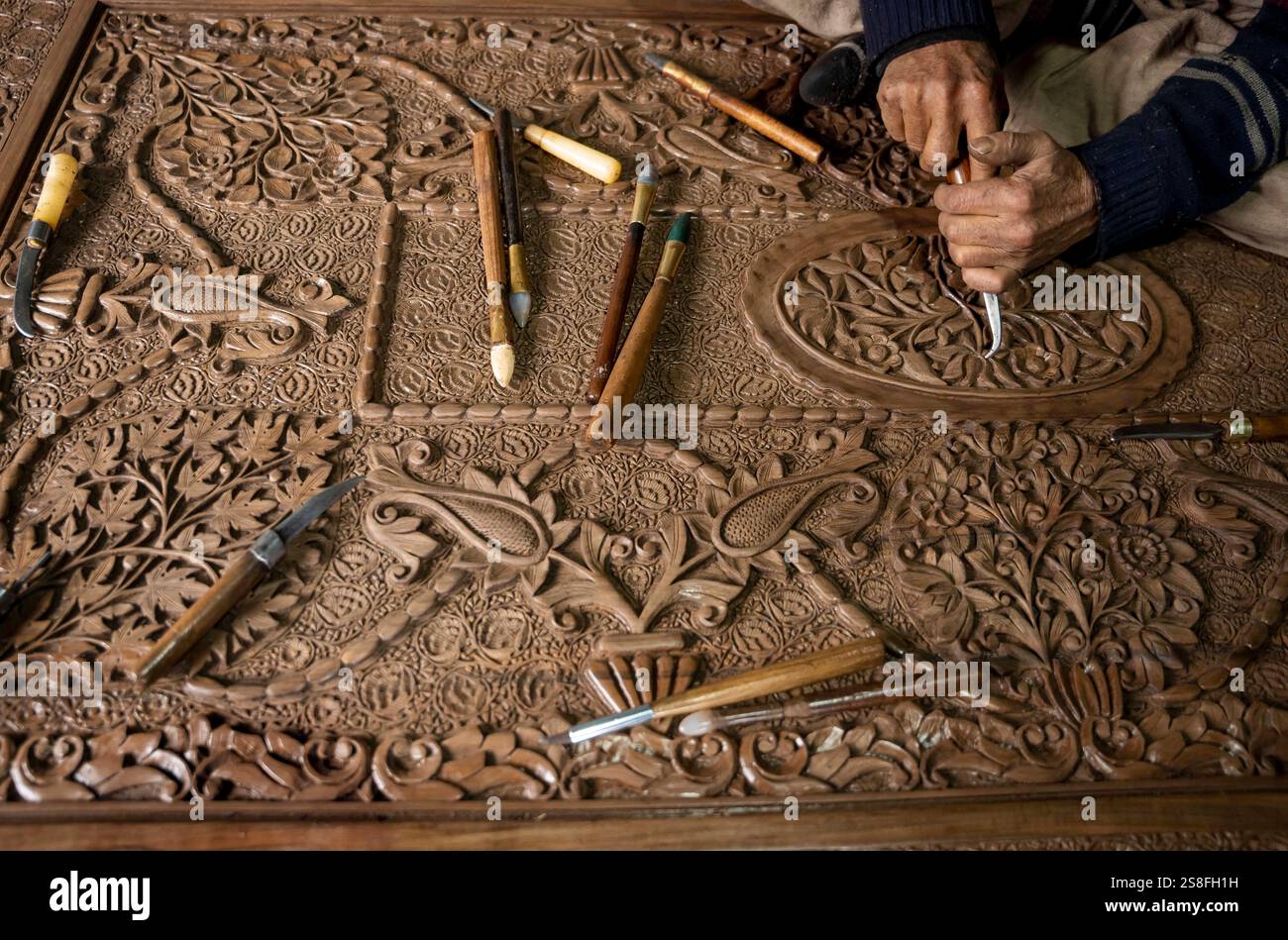A craftsman is seen using a tool to brighten and polish a wood-crafted ...