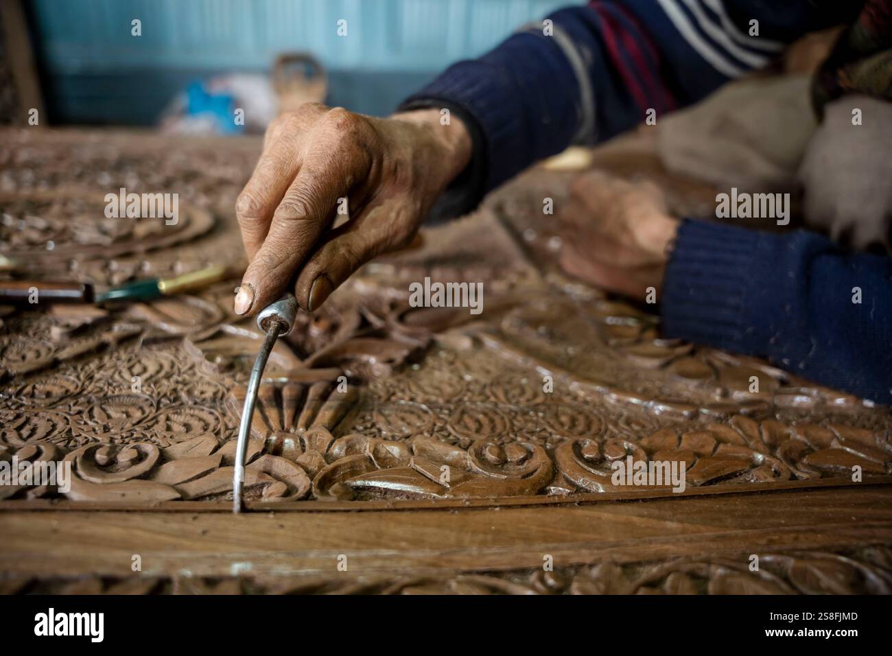 A craftsman is seen using a tool to brighten and polish a wood-crafted ...