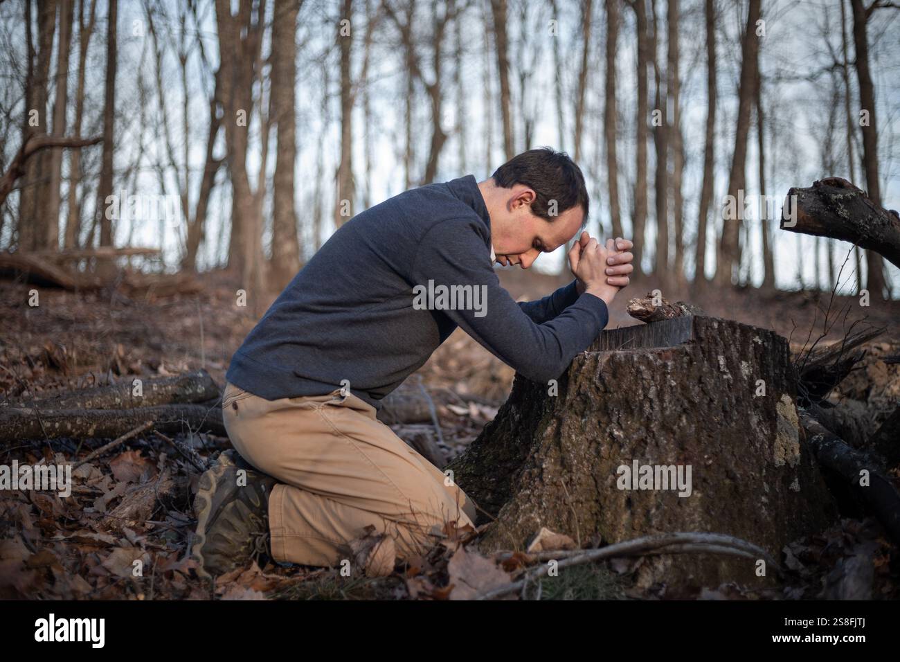 Man in woods kneeling in prayer Stock Photo - Alamy