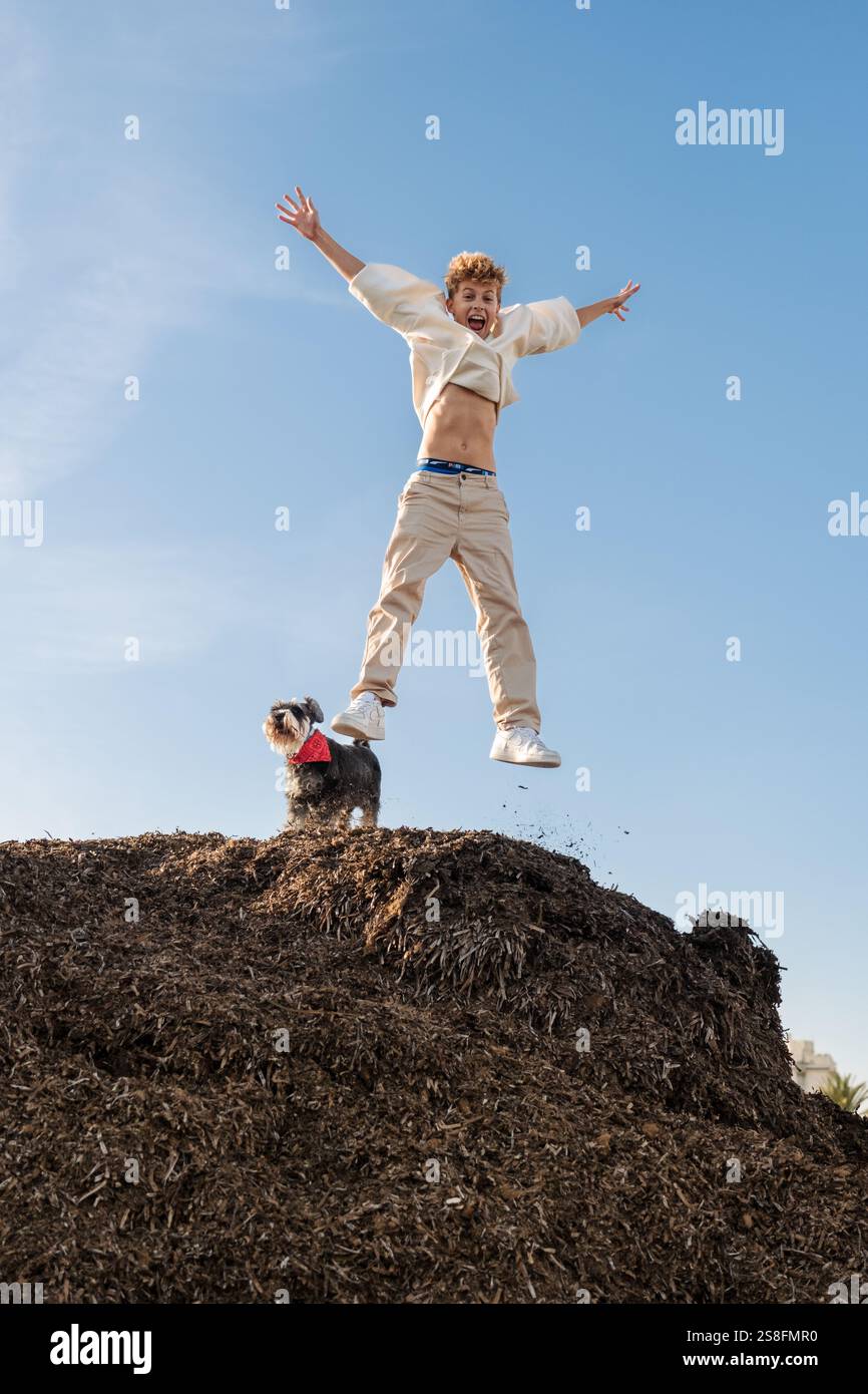 A young man leaps with excitement beside a cute dog on a sunny day The ...