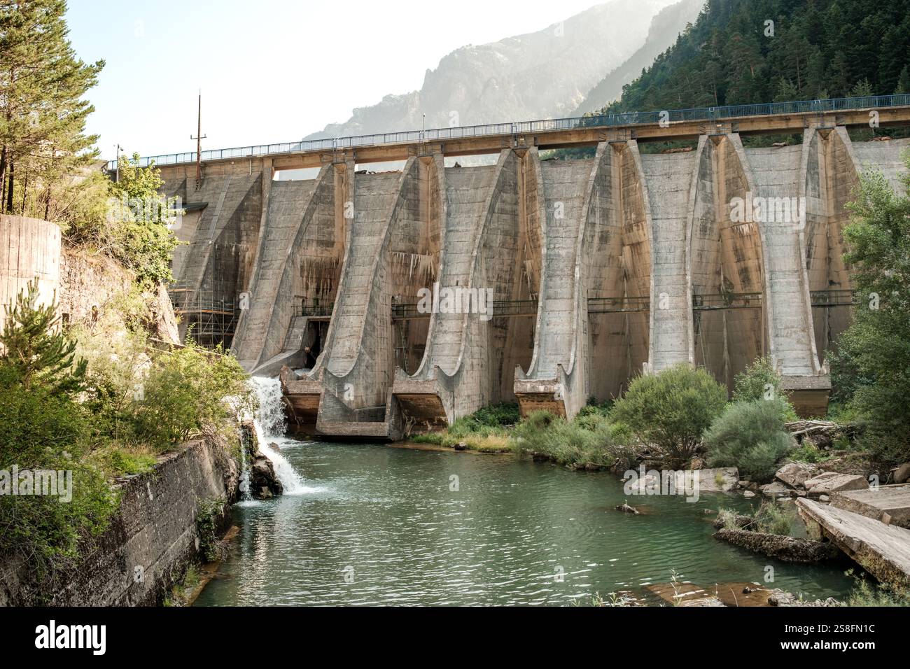 Striking view of a large concrete dam with arched spillways, surrounded ...
