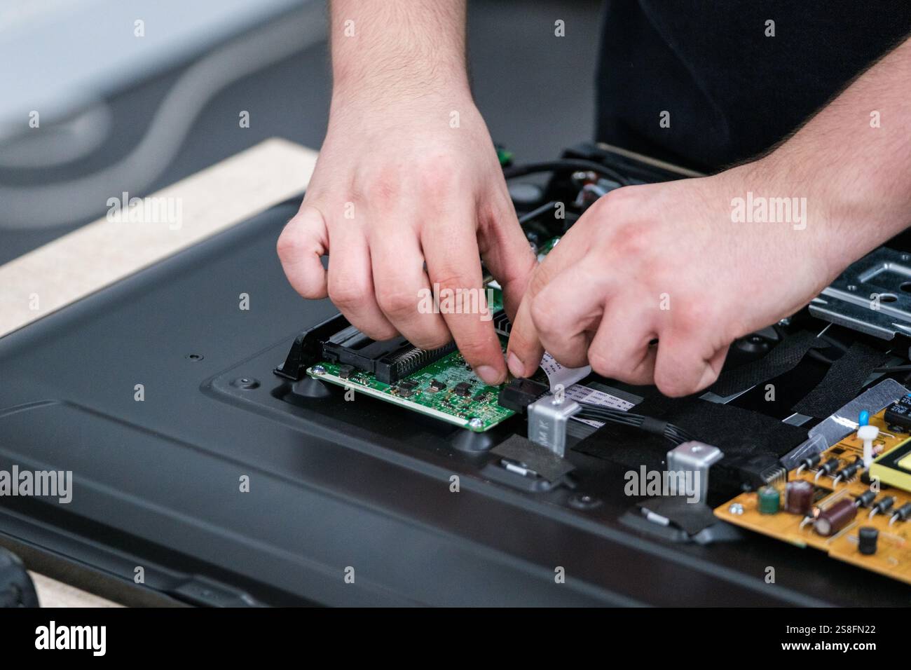 A technician diligently repairs a TV circuit board, focusing on ...