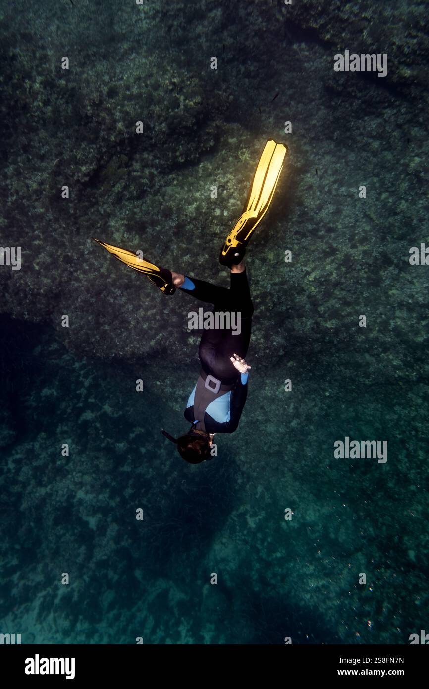 A diver descends into the clear, blue waters of Menorca, Spain ...