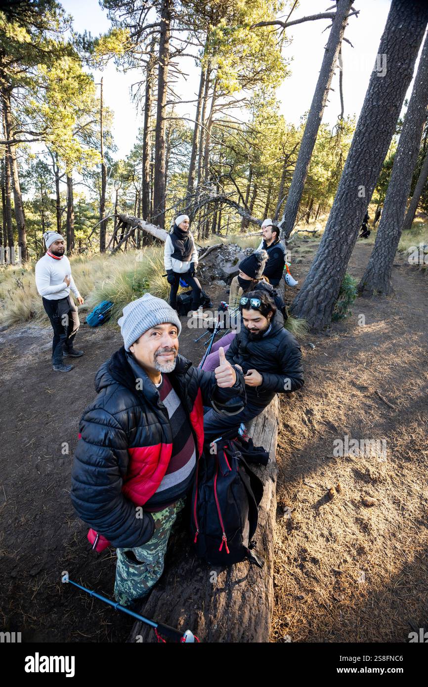 A group of mountaineers climbing a volcano, surrounded by dense forest ...