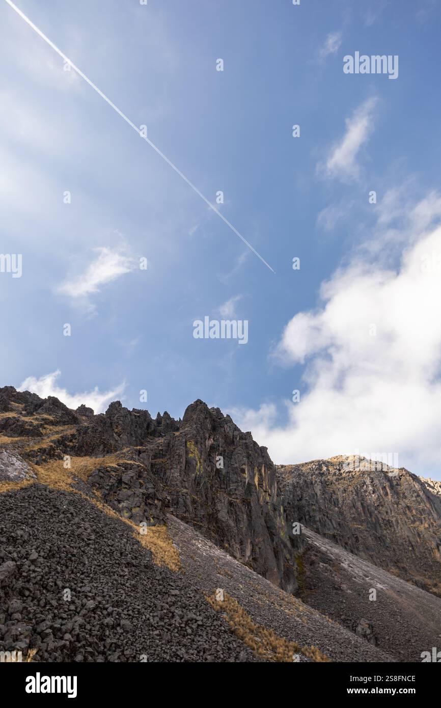 A dramatic view of a rugged volcanic cliff beneath a clear blue sky ...