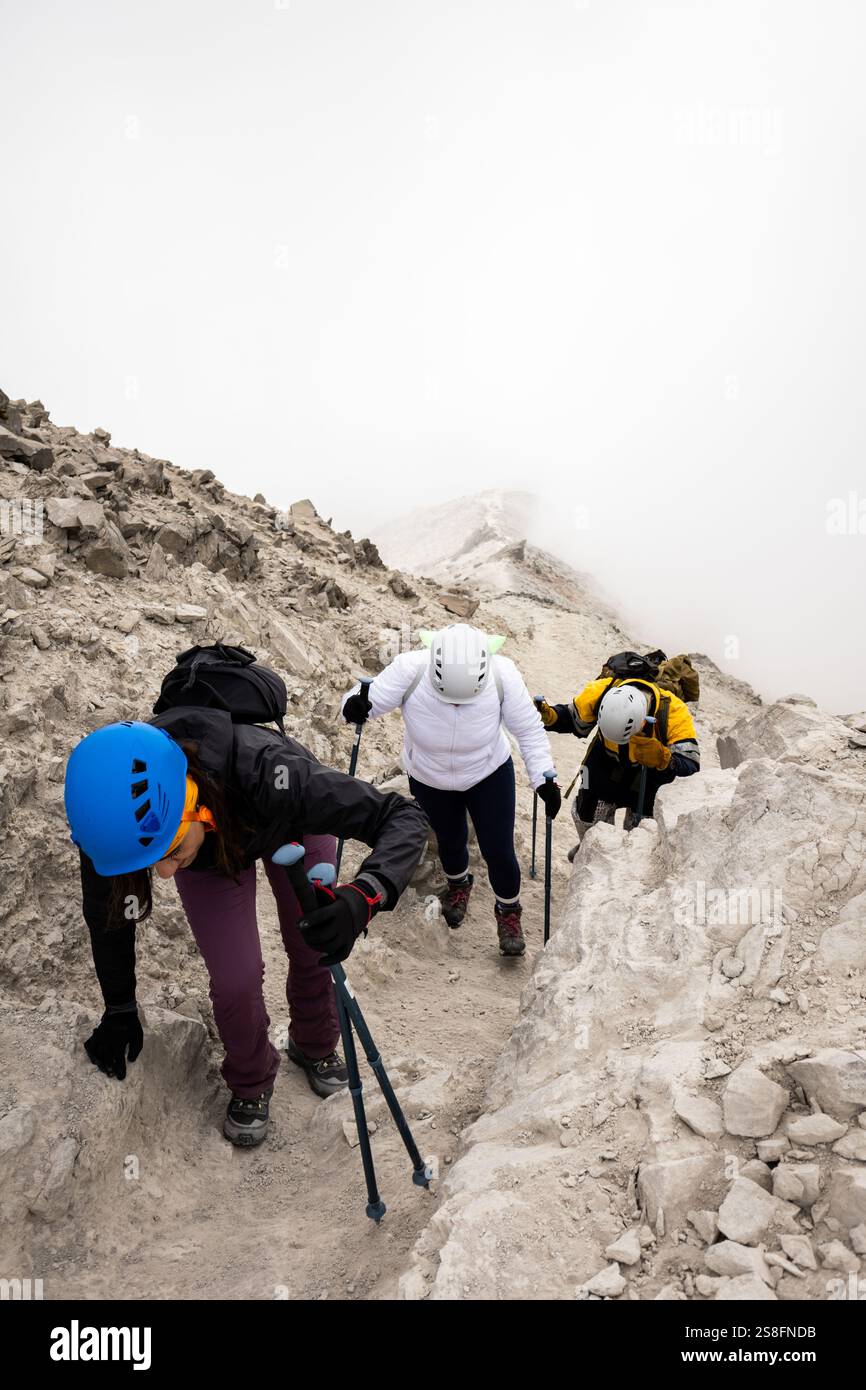 A group of mountaineers equipped with helmets and trekking poles ascend ...