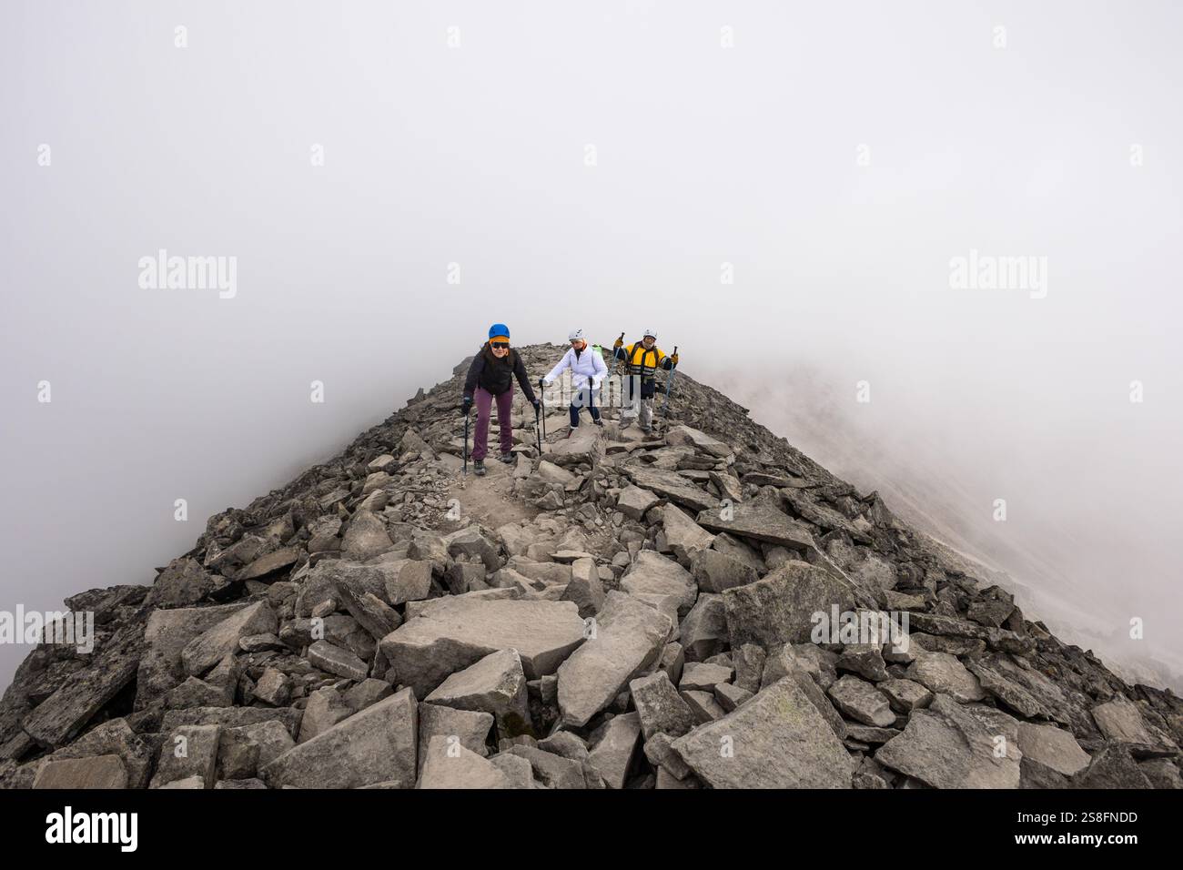 A group of mountaineers climbs a rugged volcanic trail, surrounded by ...