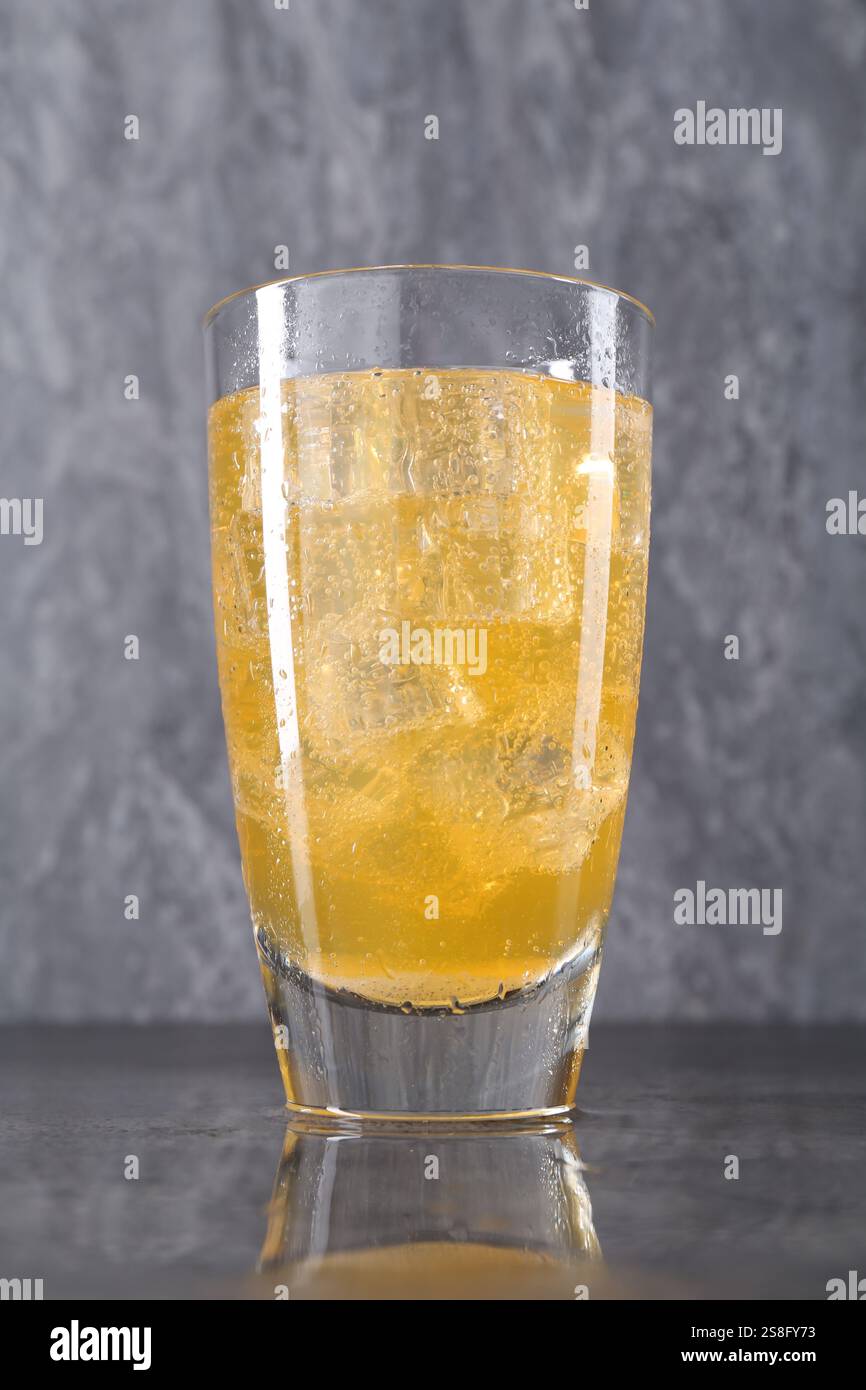 Sweet soda water with ice cubes in glass on grey table, closeup Stock ...