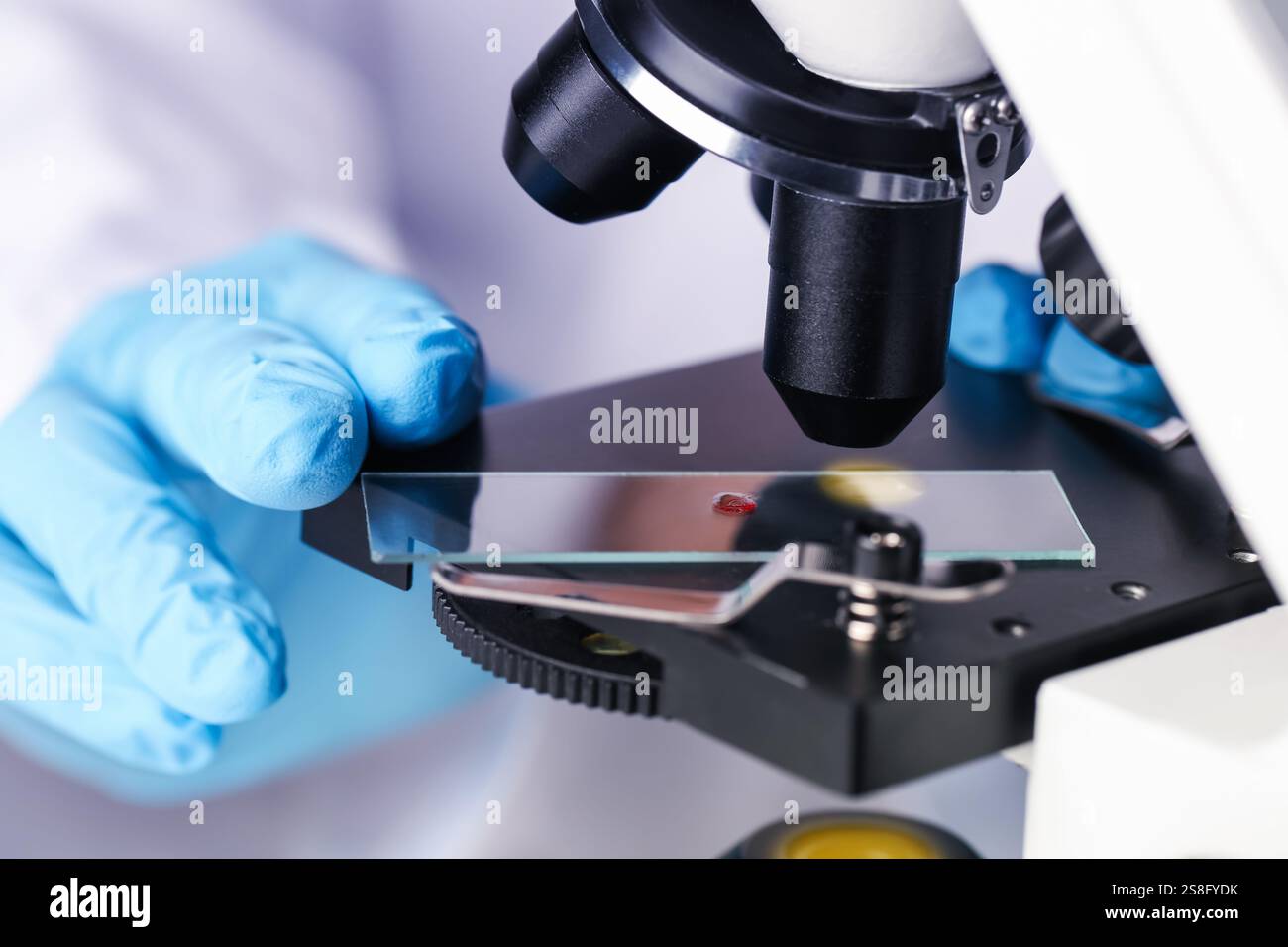 Scientist examining sample on slide under microscope, closeup Stock Photo - Alamy