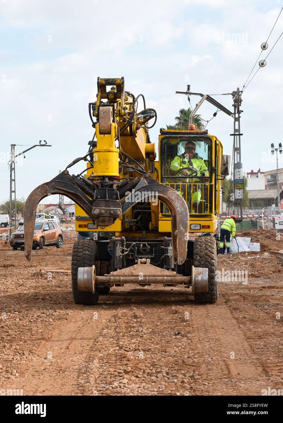 Workers with heavy machinery with clamp excavator attachment during ...