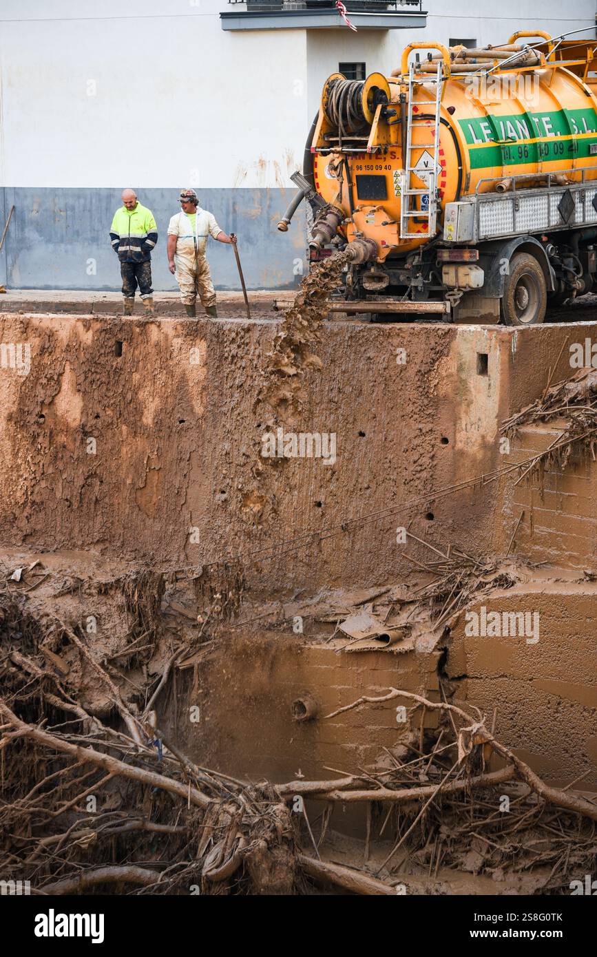Sewer dredge cleaning truck throwing mud into riverbed of Poyo ravine ...