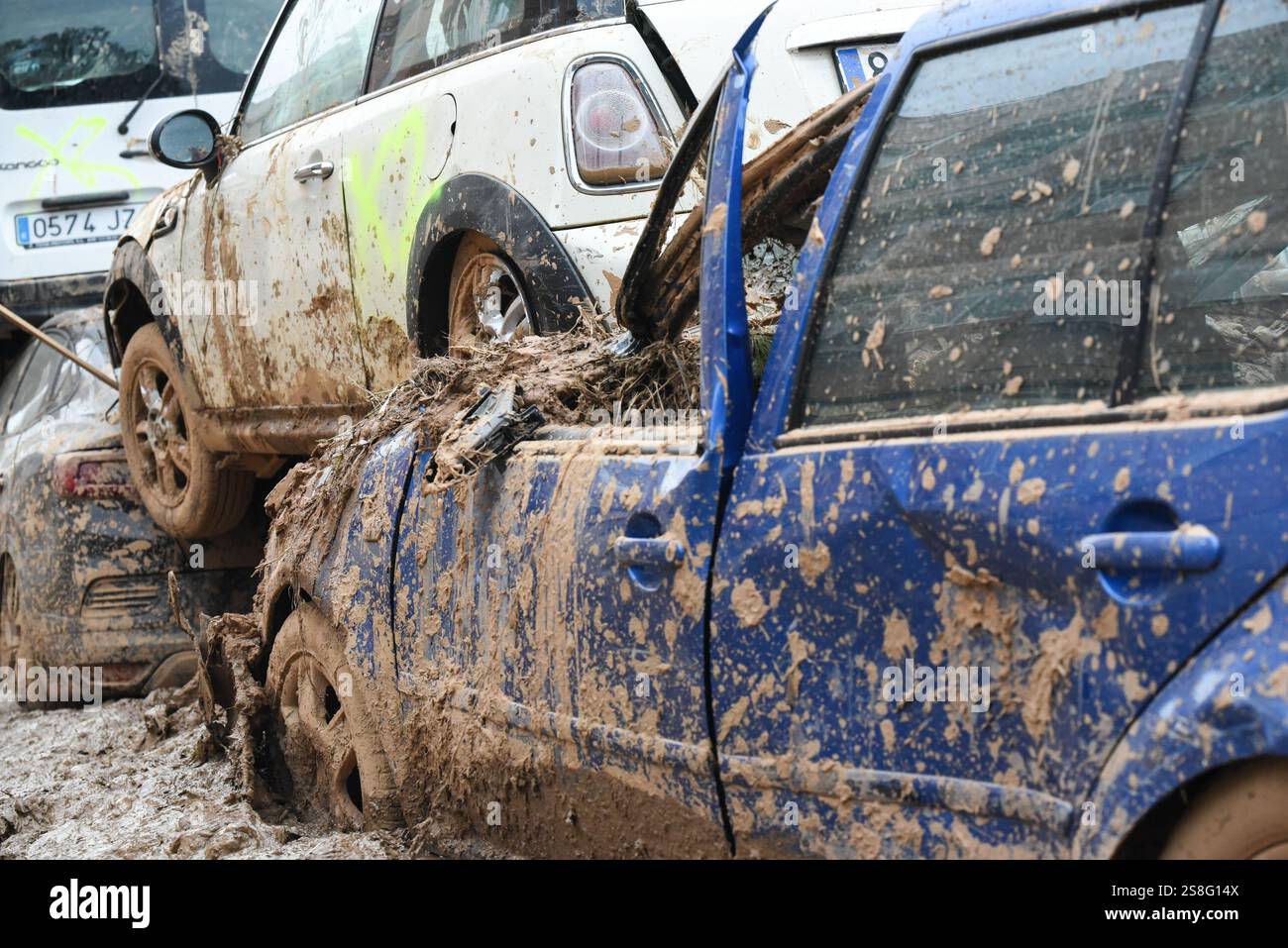 Close view of crushed cars covered in mud and piled up stuck in mud ...