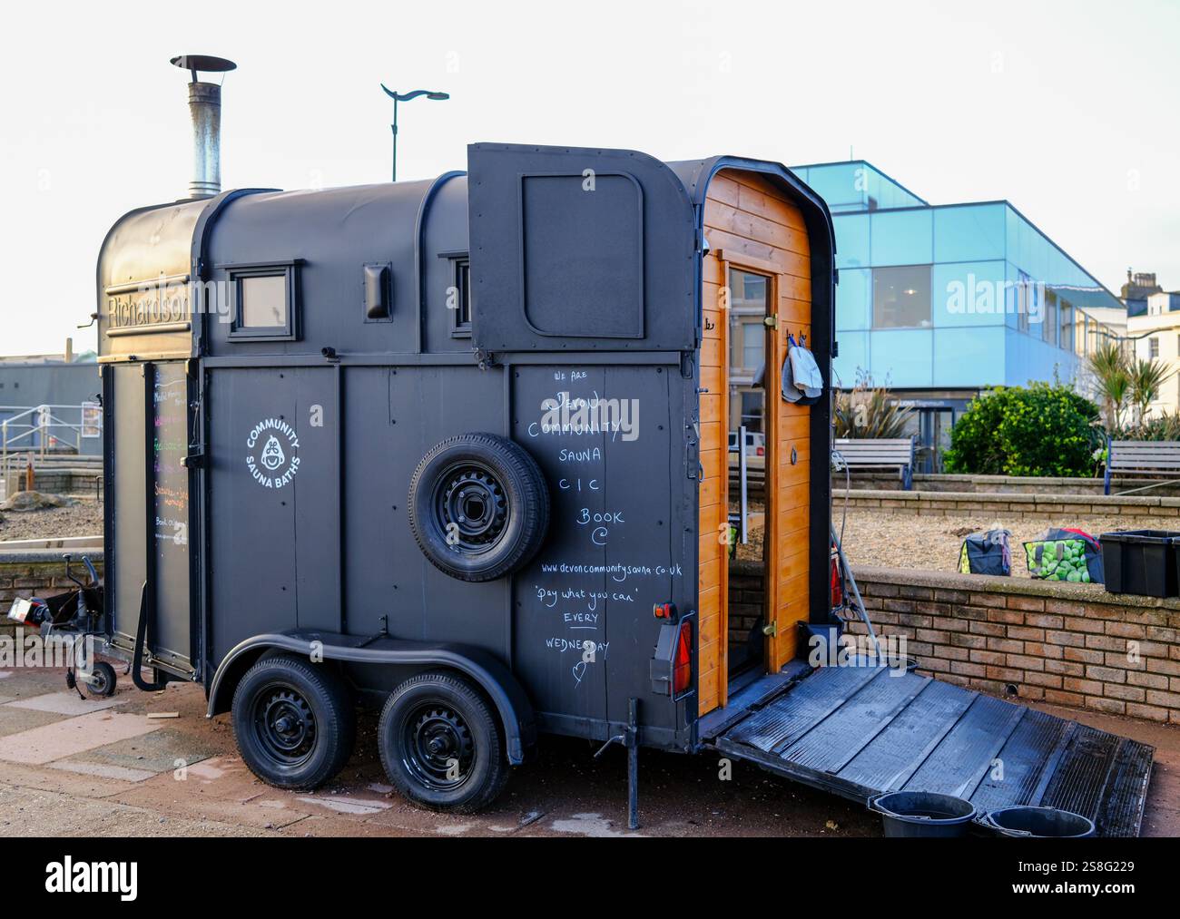 A young girl reads the signage on a mobile sauna on Teignmouth seafront ...