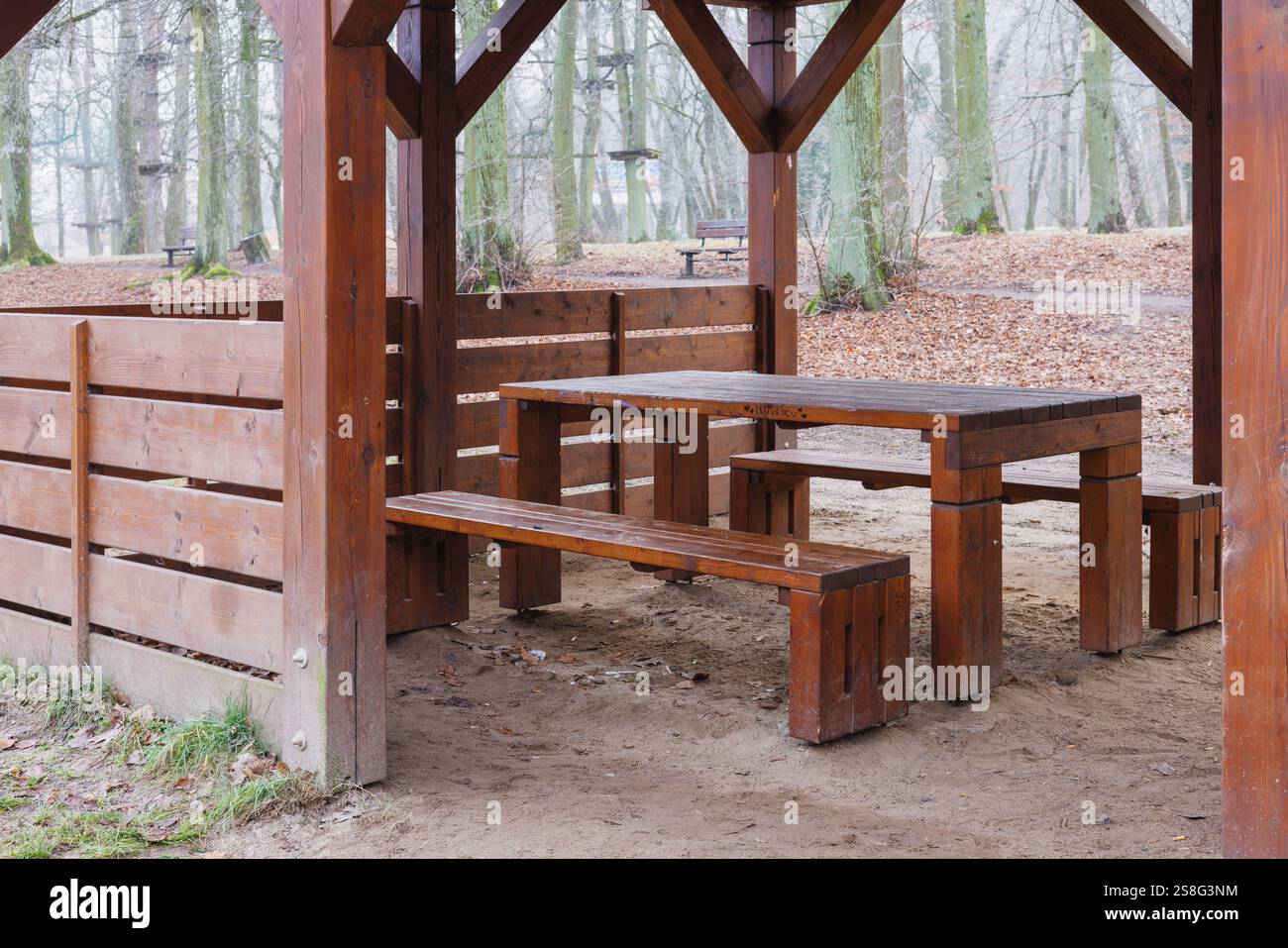 Large wooden table and benches inside the gazebo. Large square beams ...