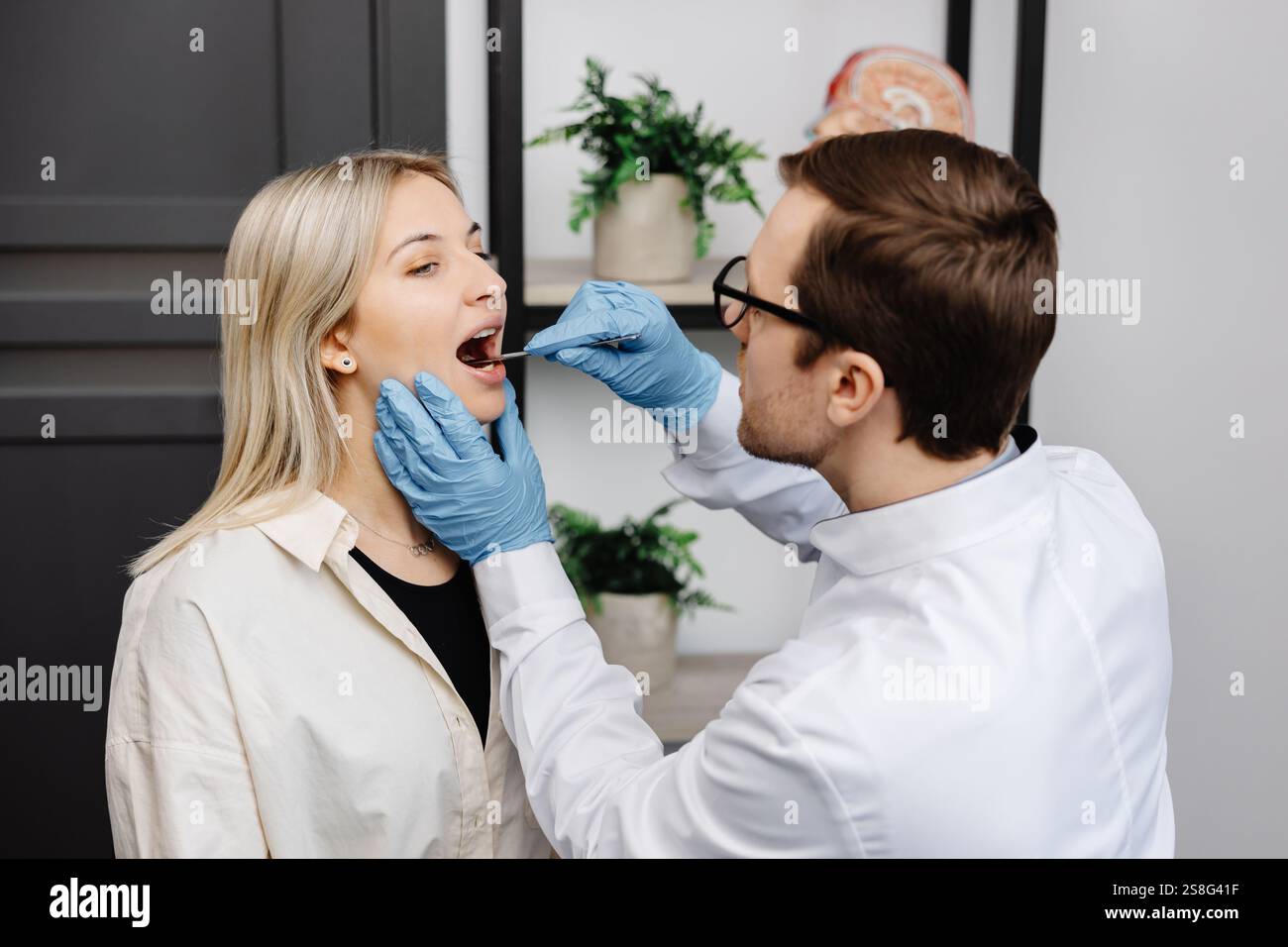 Doctor using inspection spatula to examine patient throat. ENT doctor ...