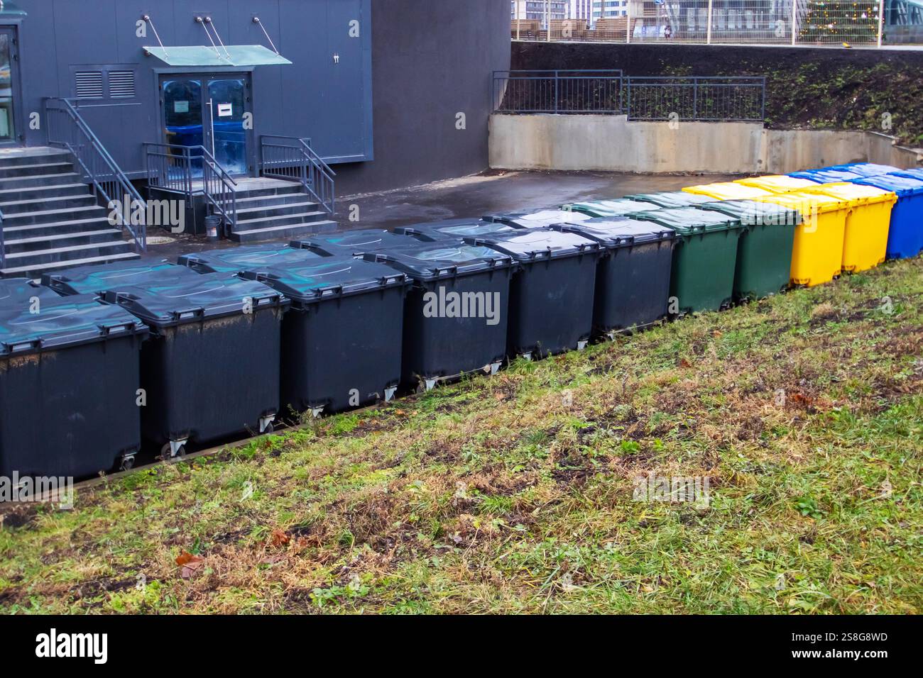 A neat row of trash cans is strategically lined up in front of a large ...