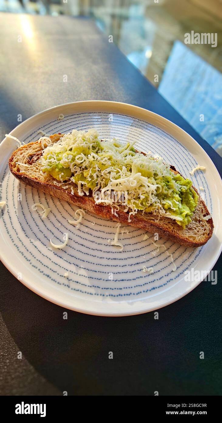 Smashed avocado sandwich on toasted bread with grated cheese in round ...