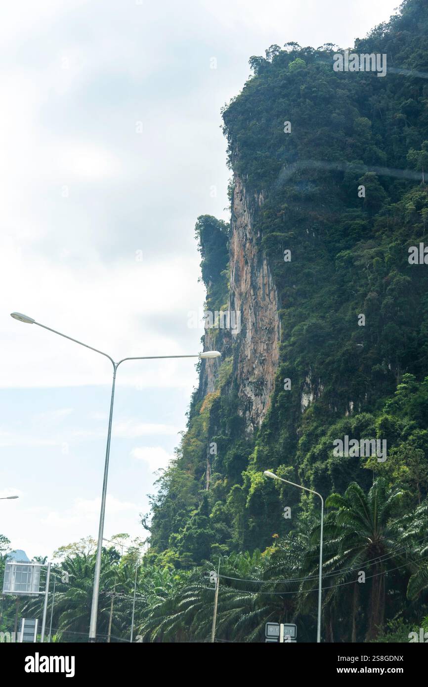Towering limestone cliffs rise above the tropical landscape near a ...