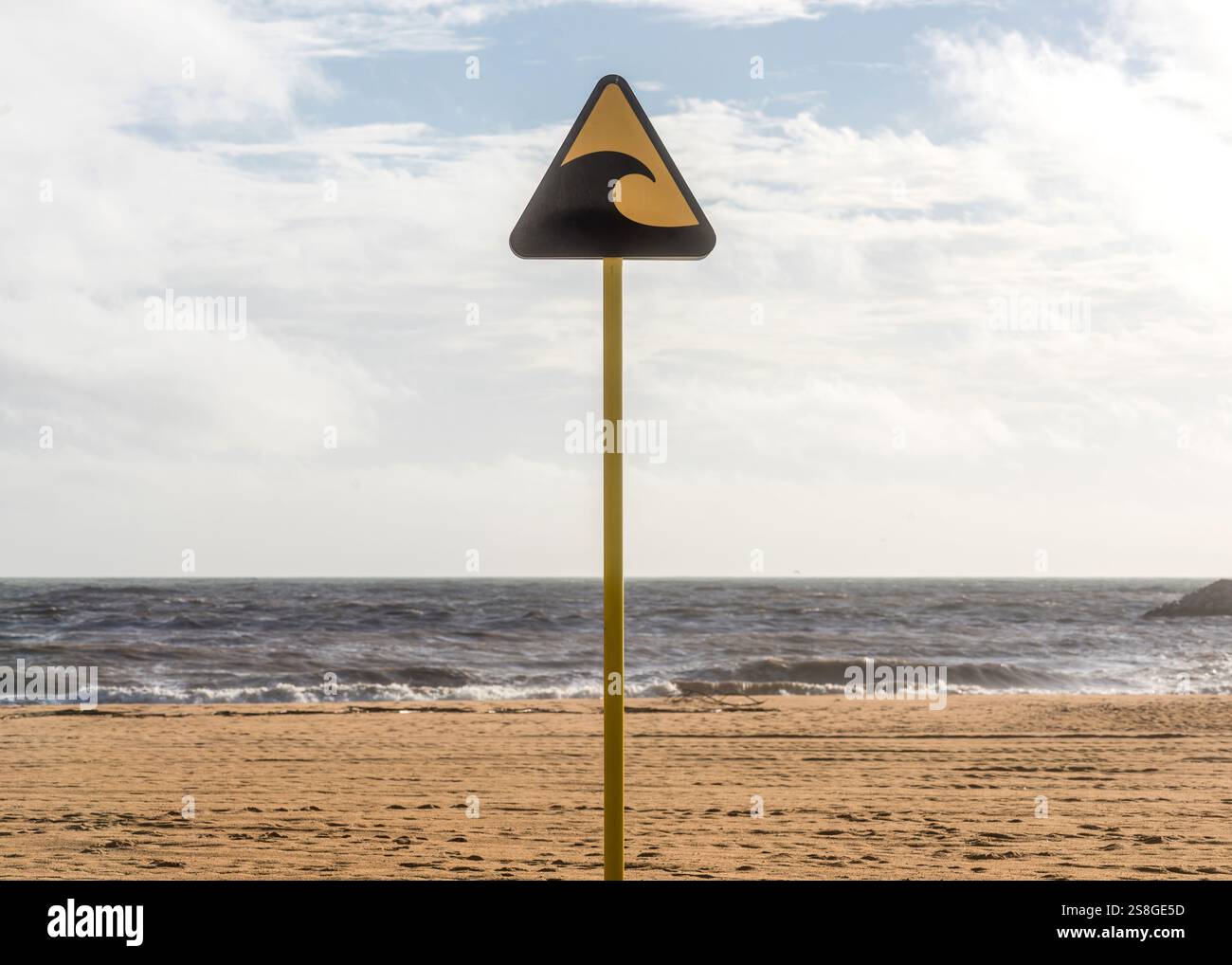 A warning sign indicating a tsunami hazard is displayed on an empty ...