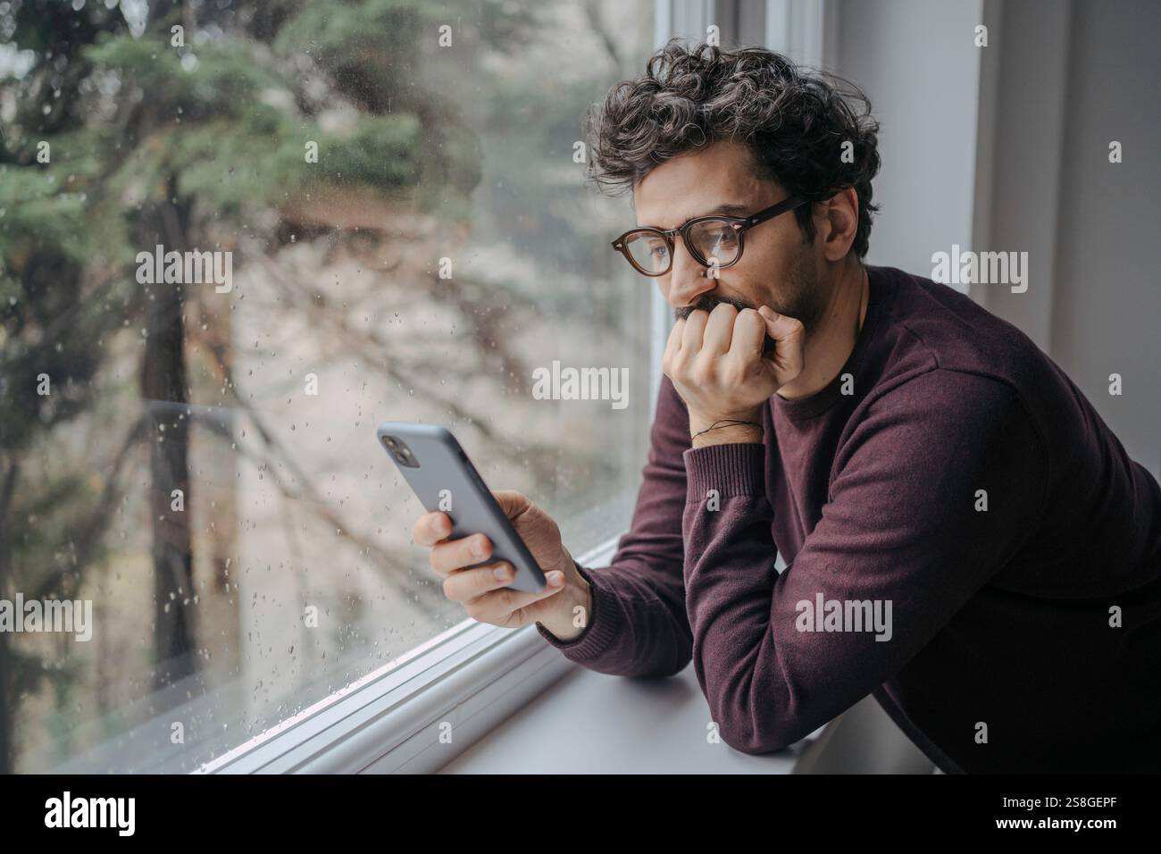 Adult middle eastern good looking man with glasses is scrolling on mobile phone in the morning ...