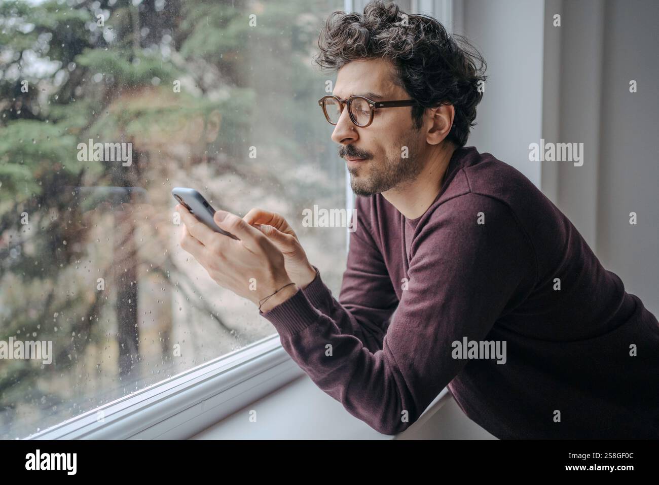 Adult middle eastern good looking man with glasses is scrolling on mobile phone in the morning ...