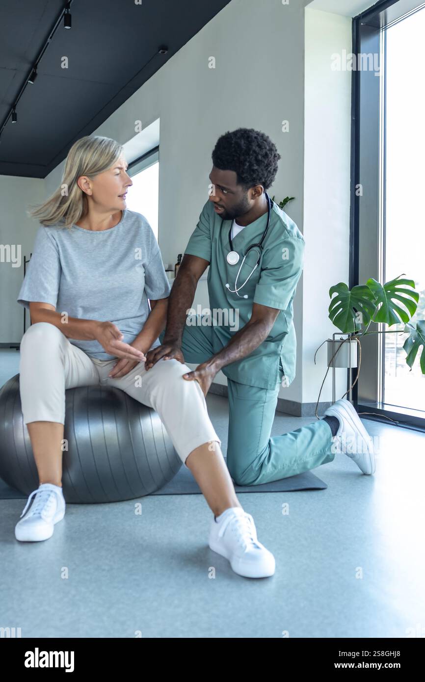 Orthopedic specialist helping patient with knee flexion exercises ...