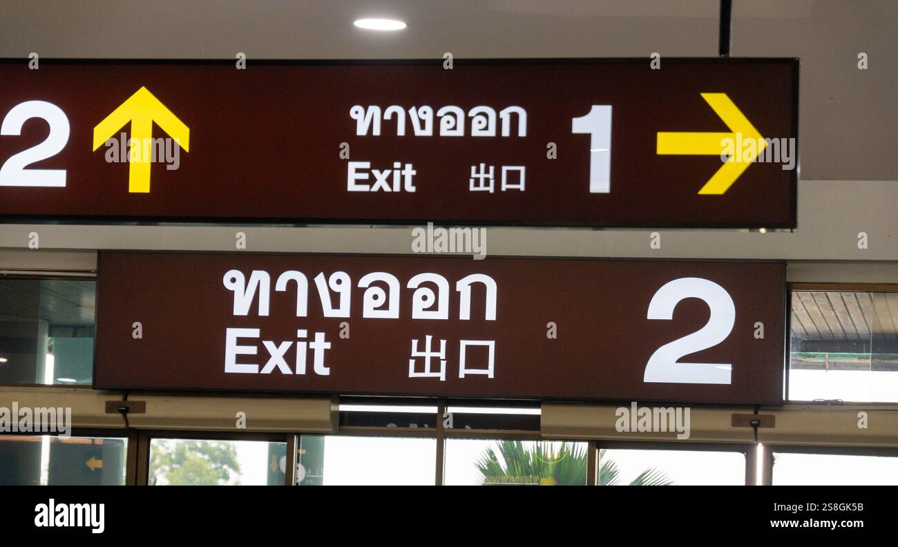 Directional signs guide travelers to exit points at a bustling airport ...