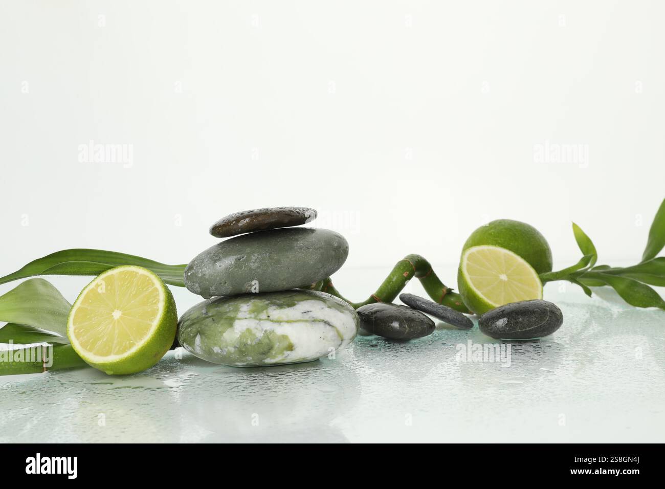 Spa composition with limes, massage stones and bamboo stem on wet ...