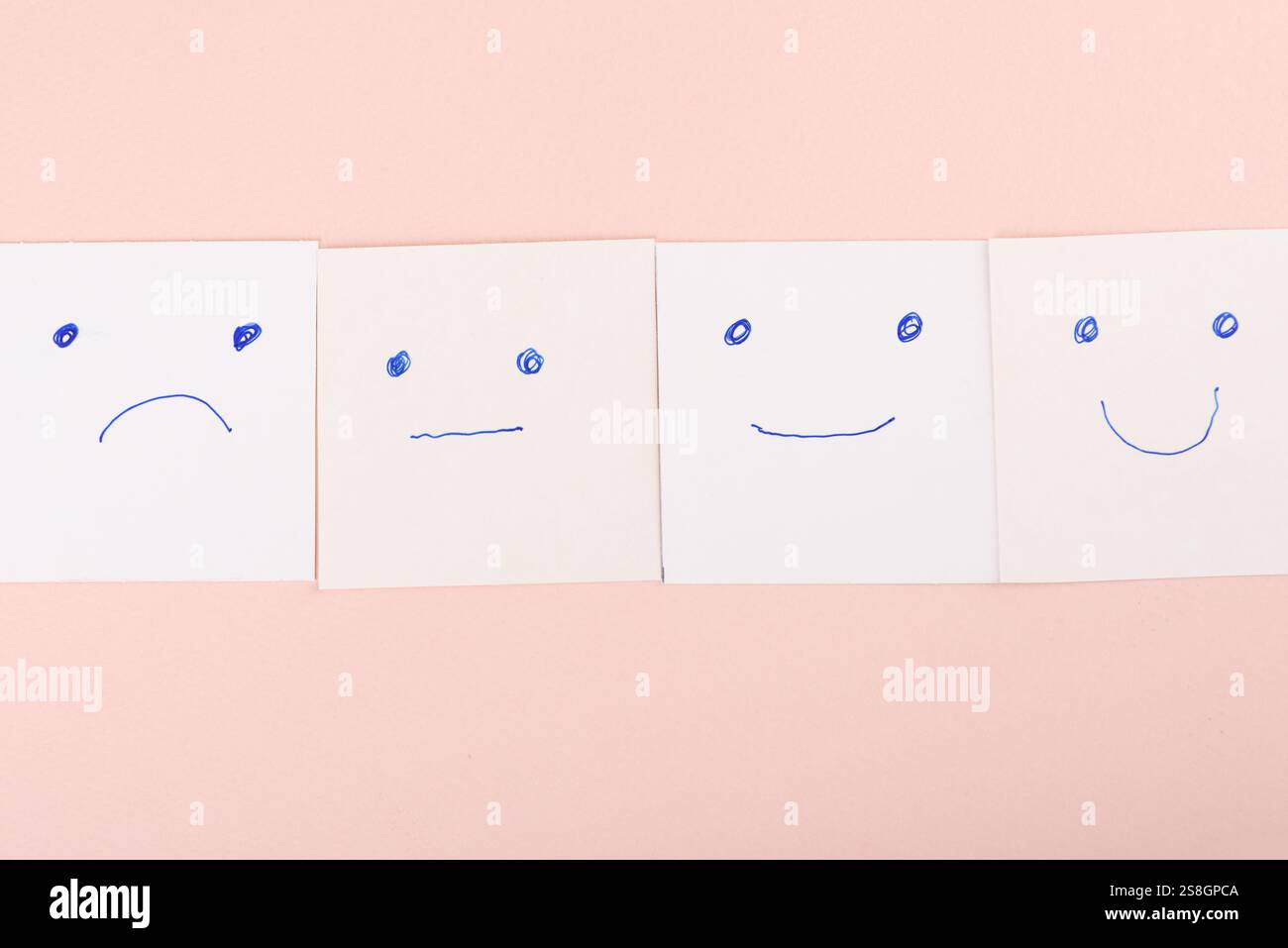 White cards with blue drawn faces showing sad and positive emotions ...