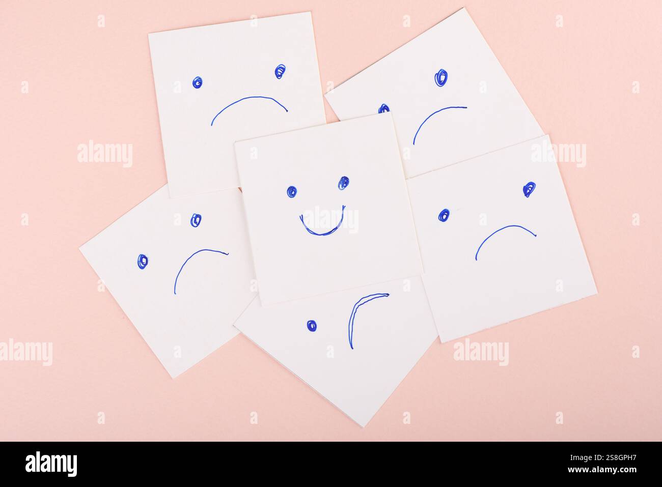 White cards with blue-drawn faces showing emotions, one smiling among ...