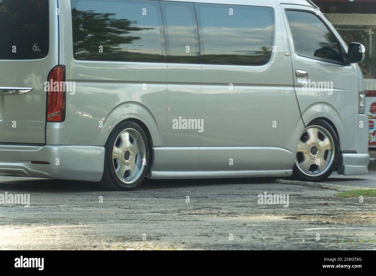 A customized silver van featuring a lowered suspension is parked on a ...