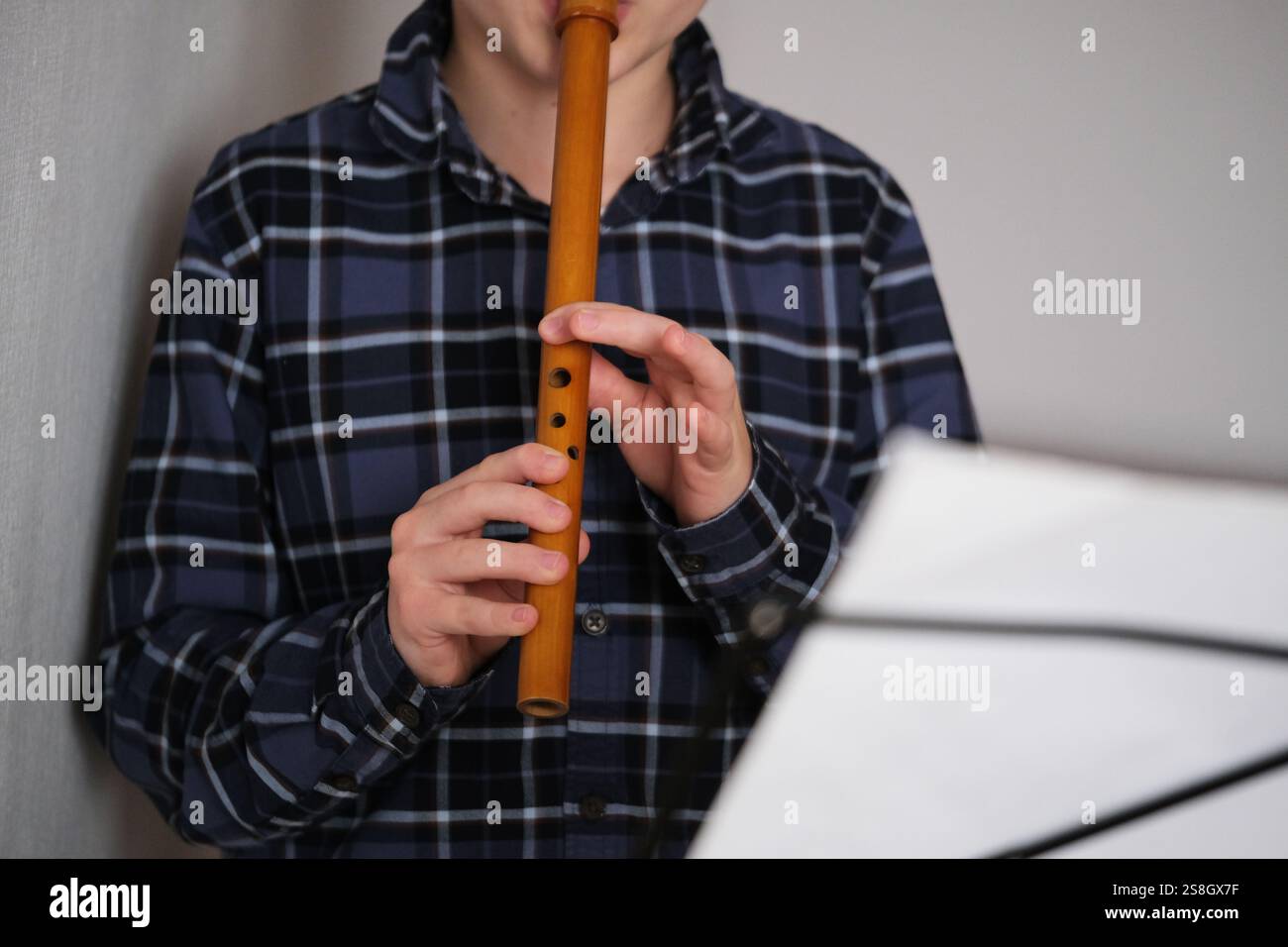 A child playing a wooden reed pipe on a gray background, music class in ...