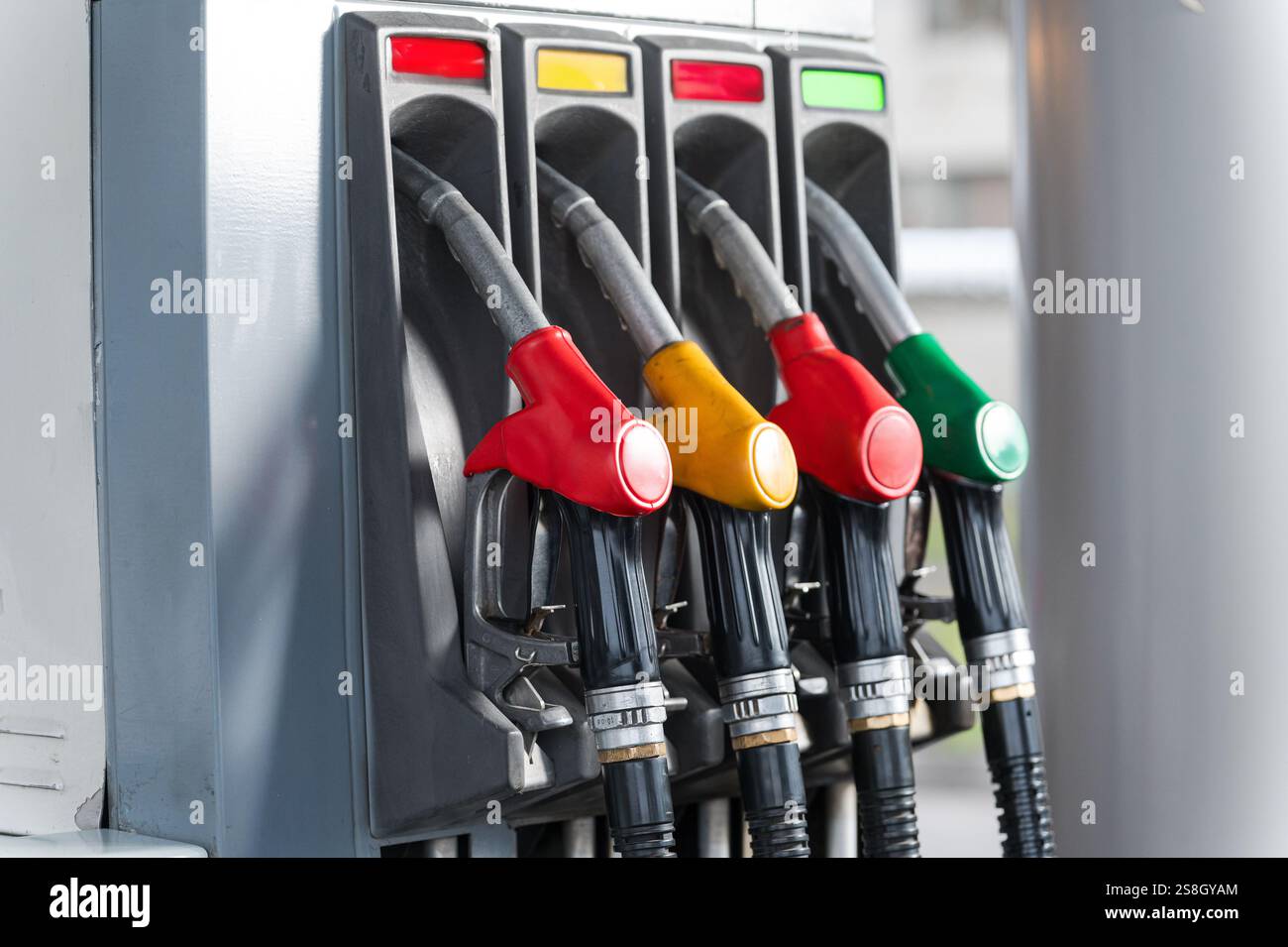 Colorful fuel pump nozzles at a modern gas station. Red, yellow, and green nozzles are aligned ...