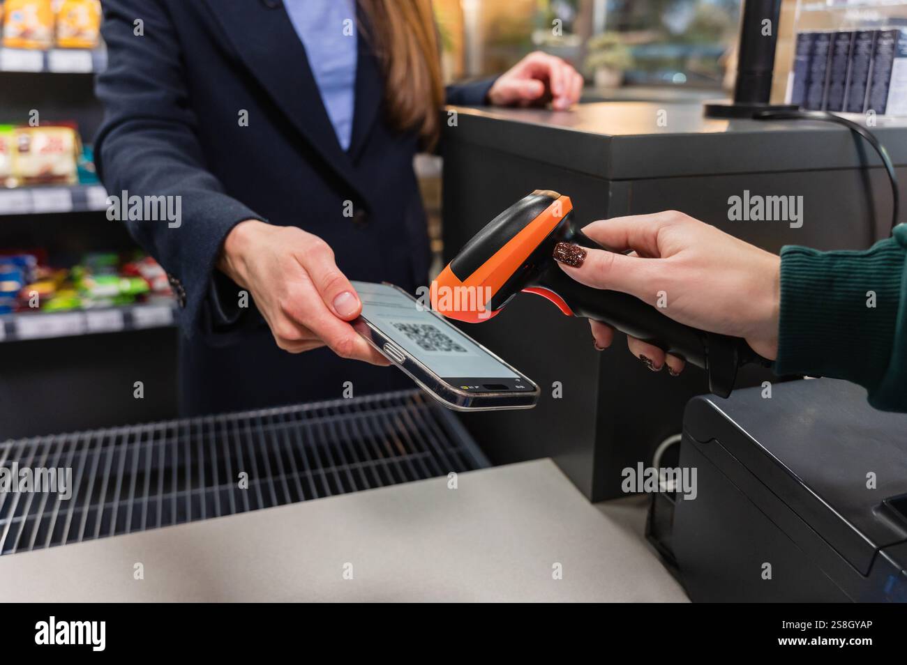 A cashier scans a qr code from a smart phone using a barcode scanner ...