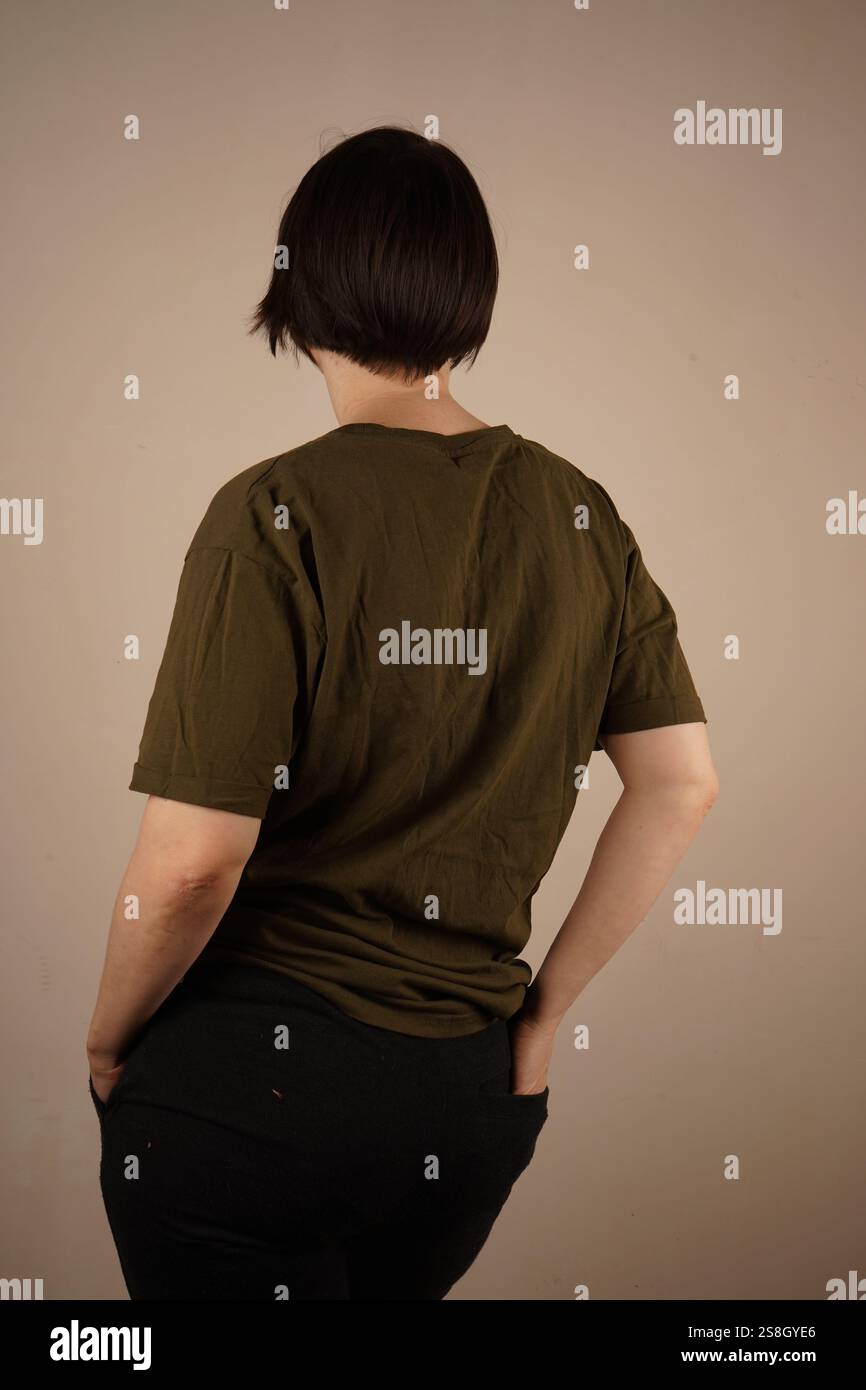 The lady opposite the gray wall put her hands in her front pockets. But ...