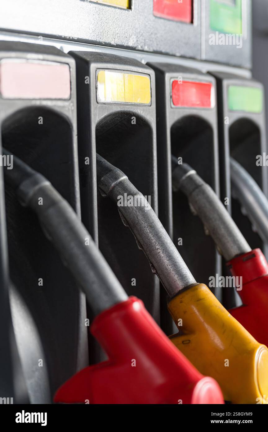 Colorful fuel pump nozzles (red, yellow, green) at a modern gas station ...