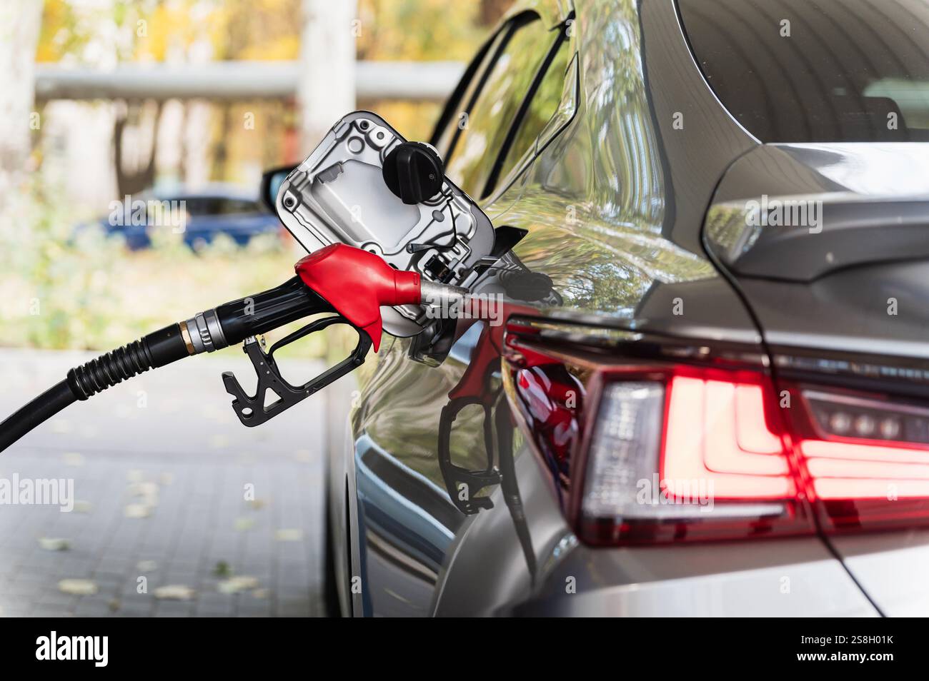 A car is refueling at a gas station. Close-up of the fuel nozzle ...