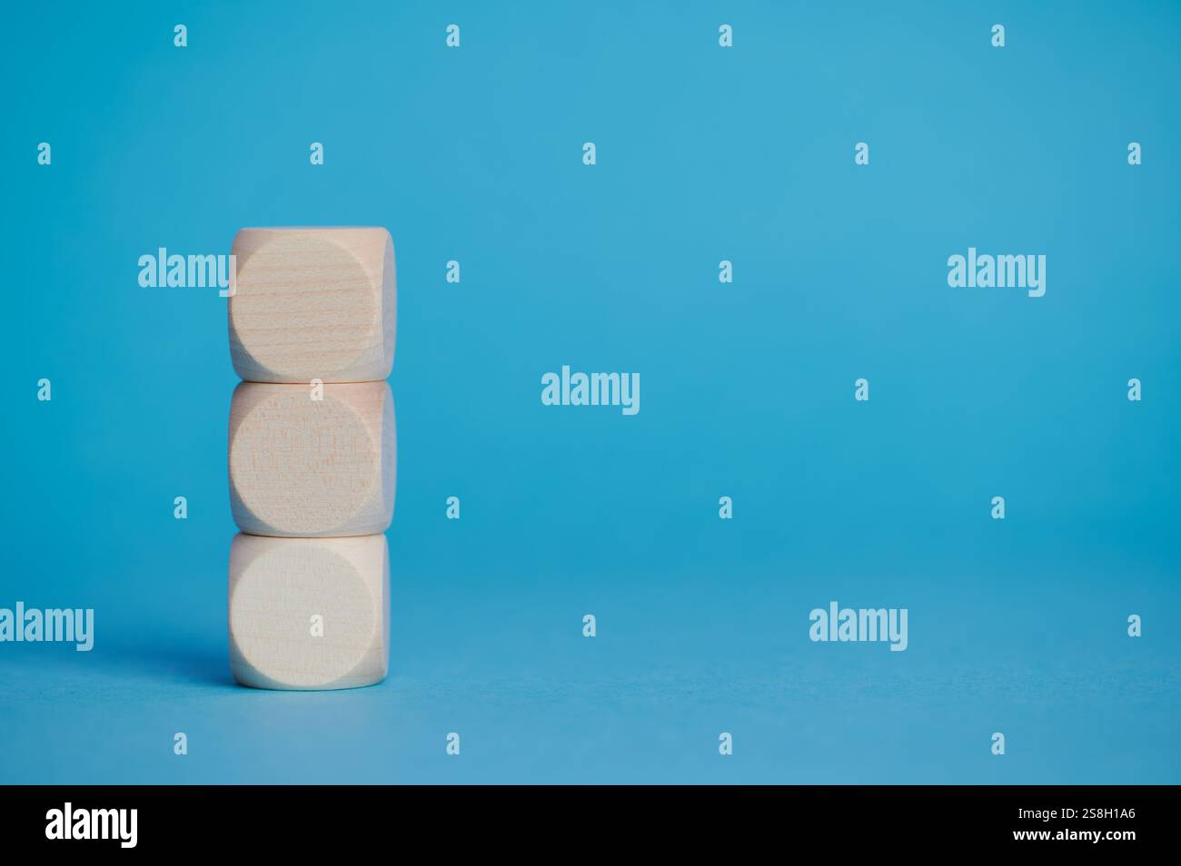 Three smooth wooden blocks stand upright against a bright blue ...